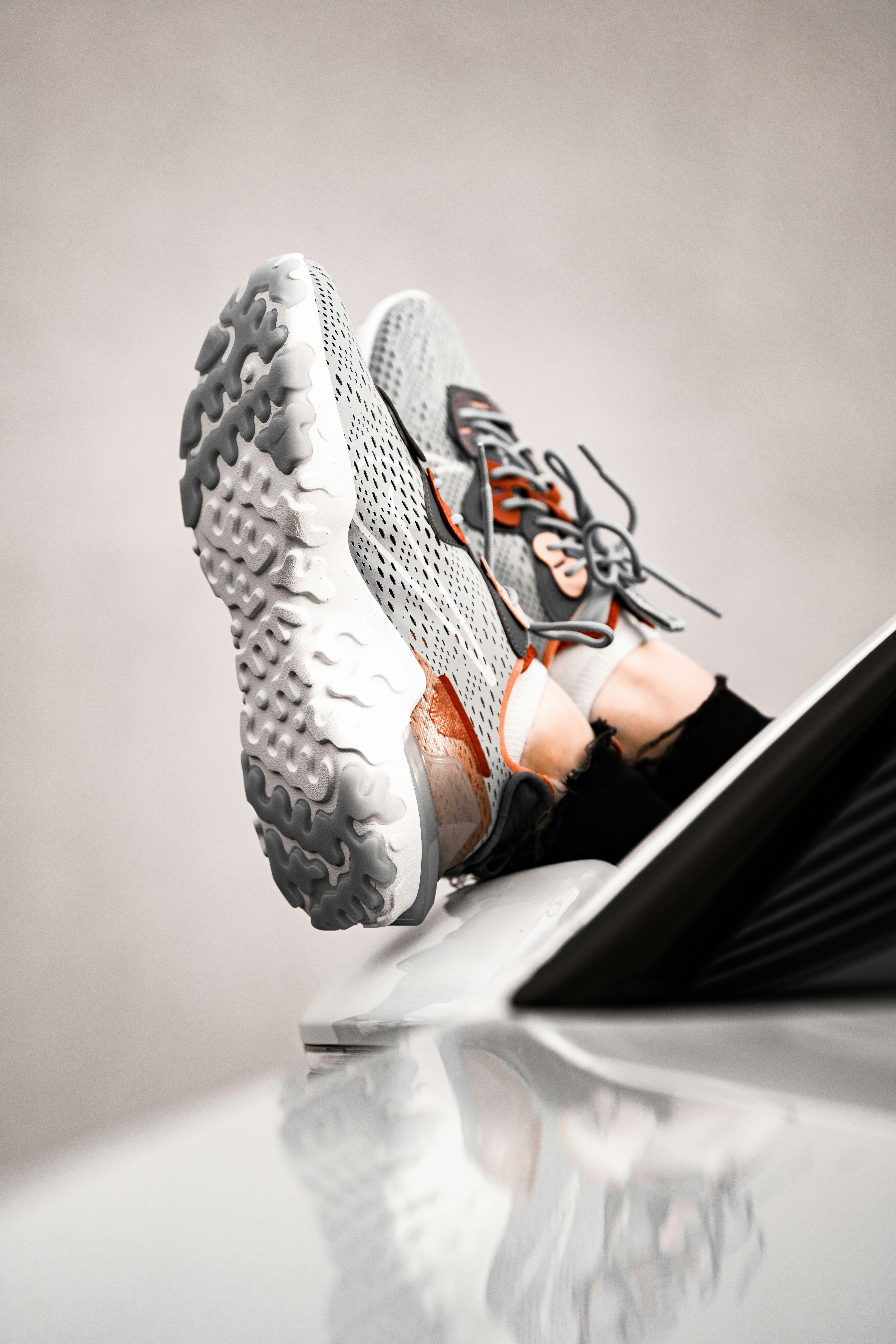 Close-up of athletic shoes resting on a sleek surface, showcasing their design and texture. The focus is on the shoe's sole and intricate details.