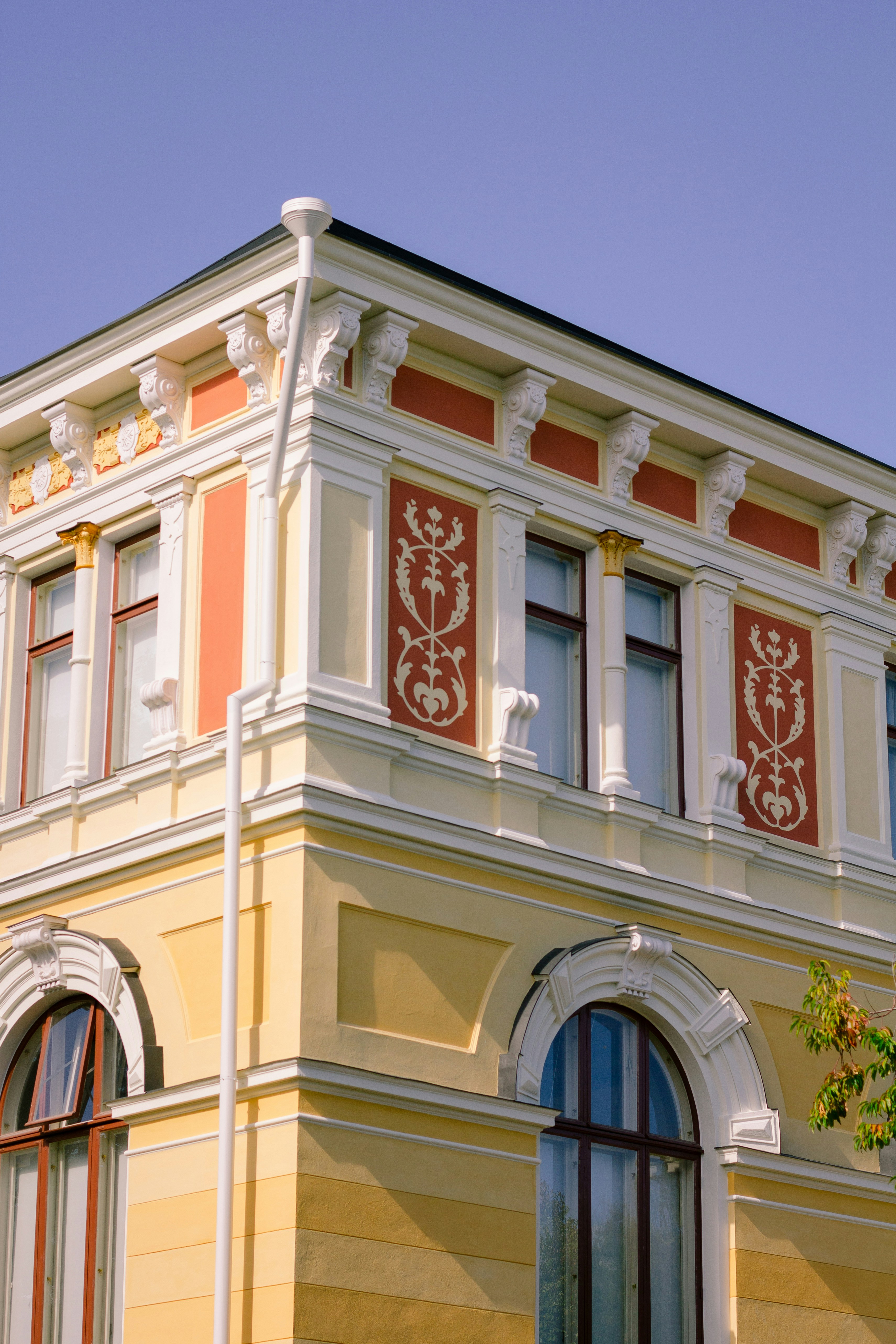 Pastel Revival: Ornate White Plasterwork Framing a Sunlit City Corner