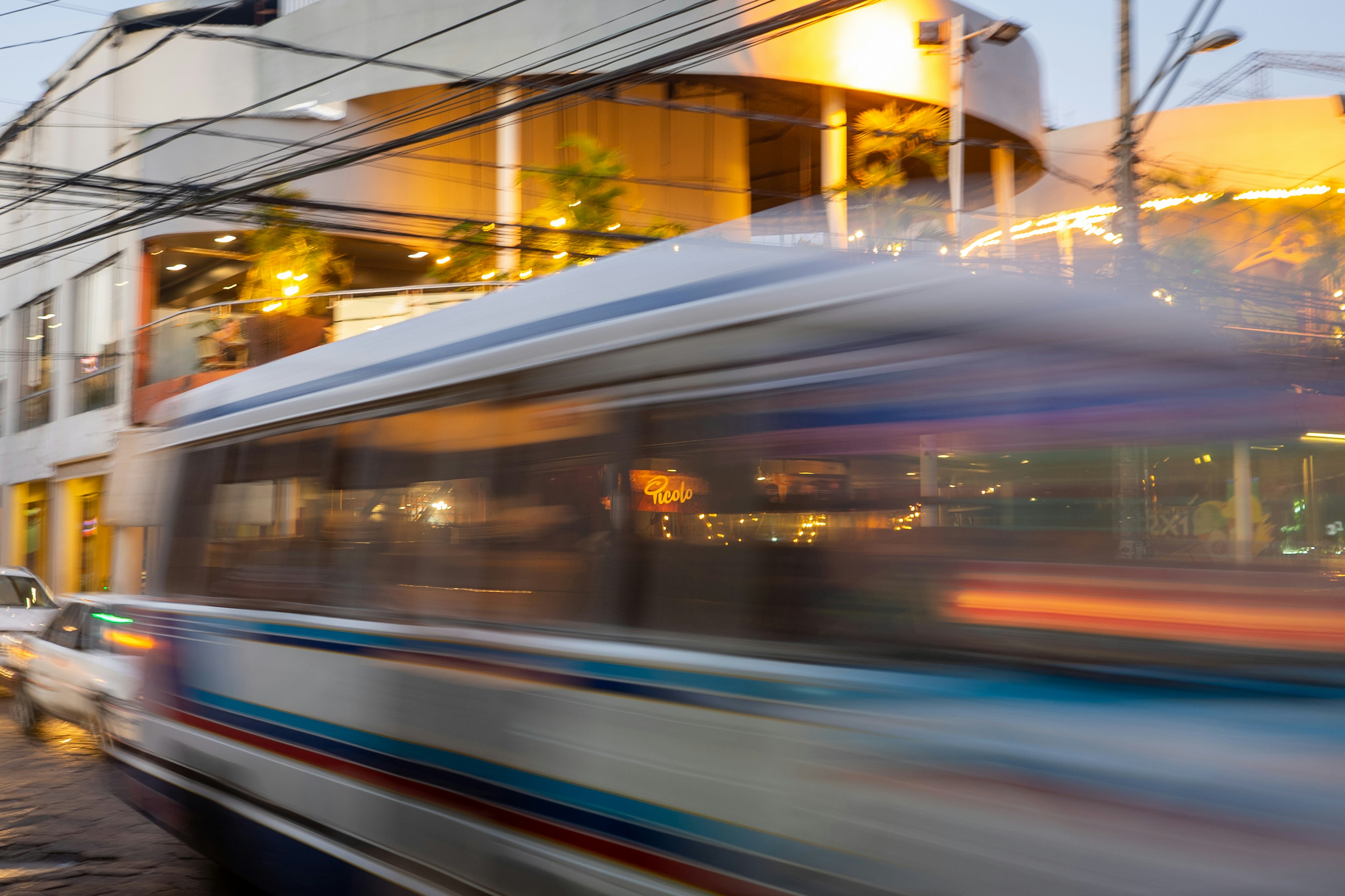 Blurred bus speeding through a city street against a backdrop of illuminated buildings.