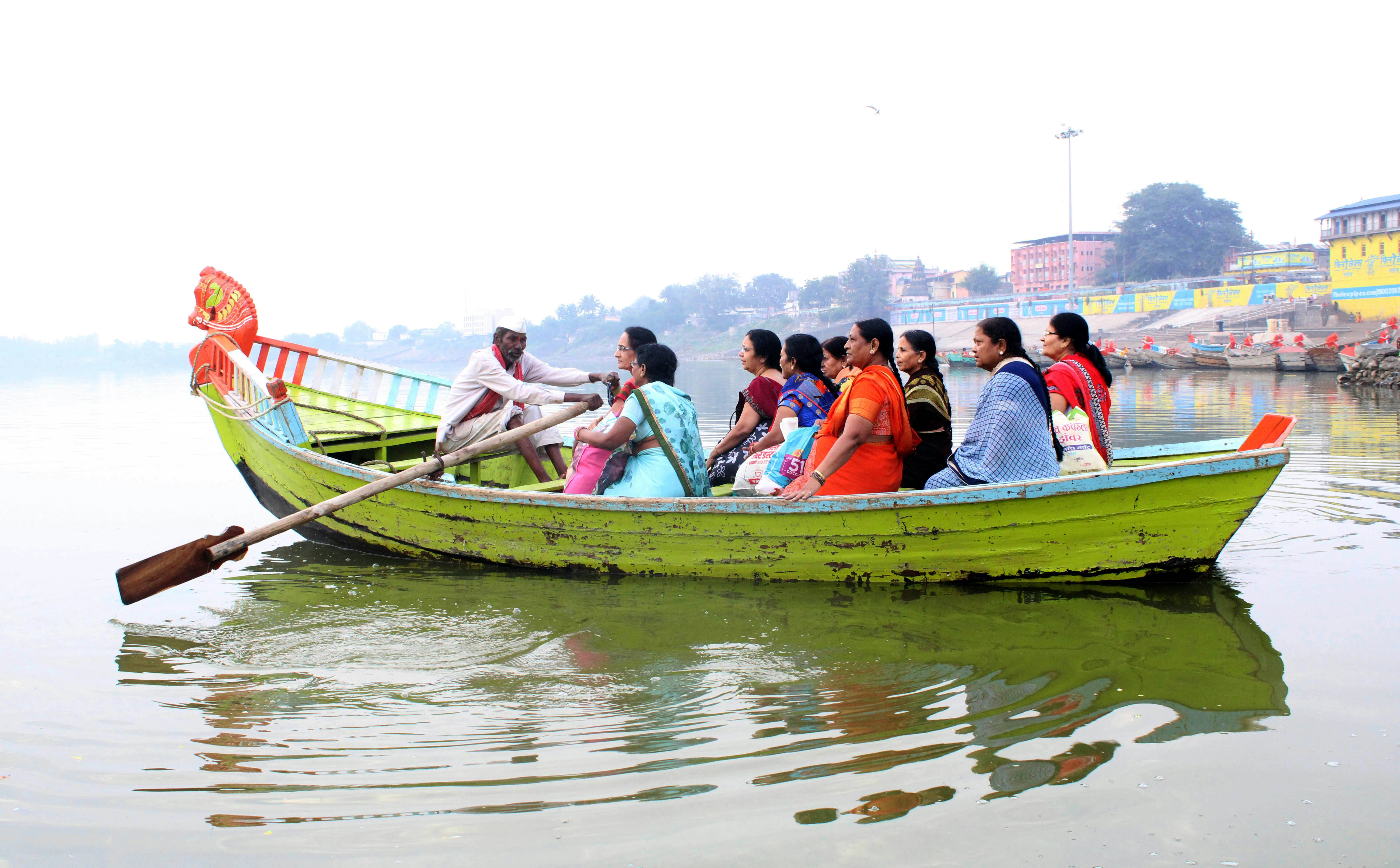 Vibrant Crossing on a Lime Hull: Sarees Adorn a Riverboat