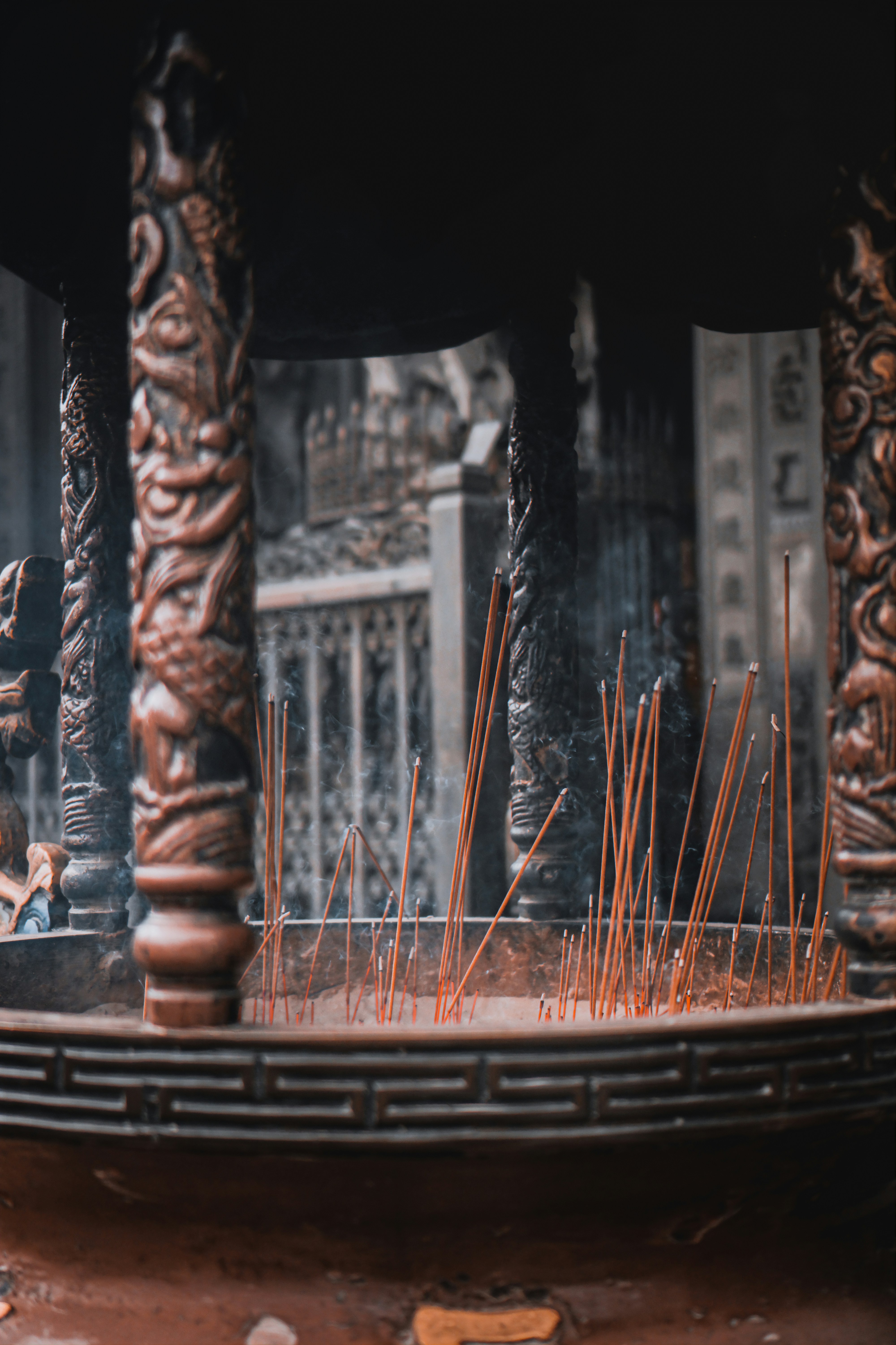 Intricately carved incense holder surrounded by burning incense sticks, enveloped in a soft veil of smoke. The scene evokes a sense of tranquility and reverence.