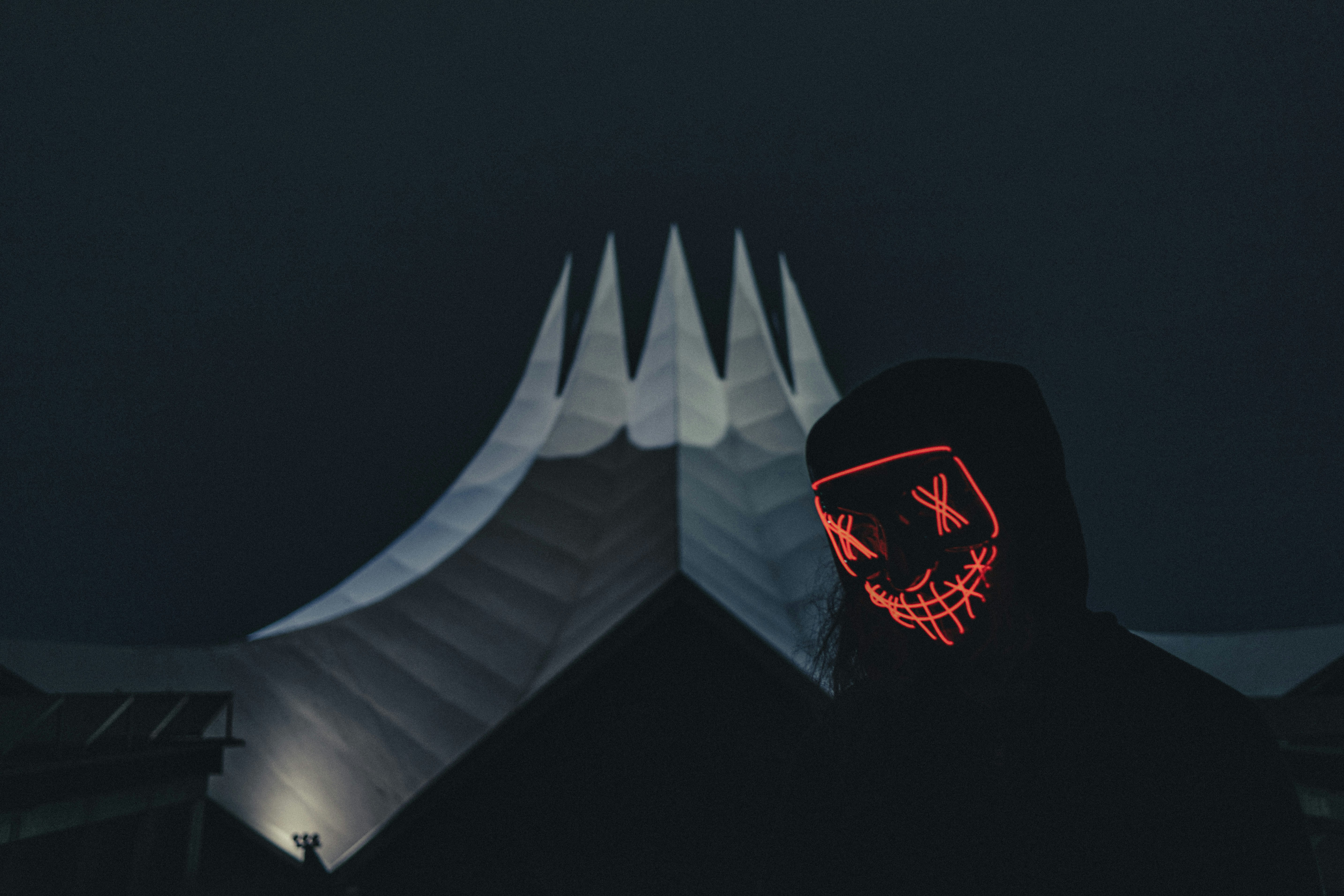 Neon Grin at Night: Hooded Figure Before Twilight Spires