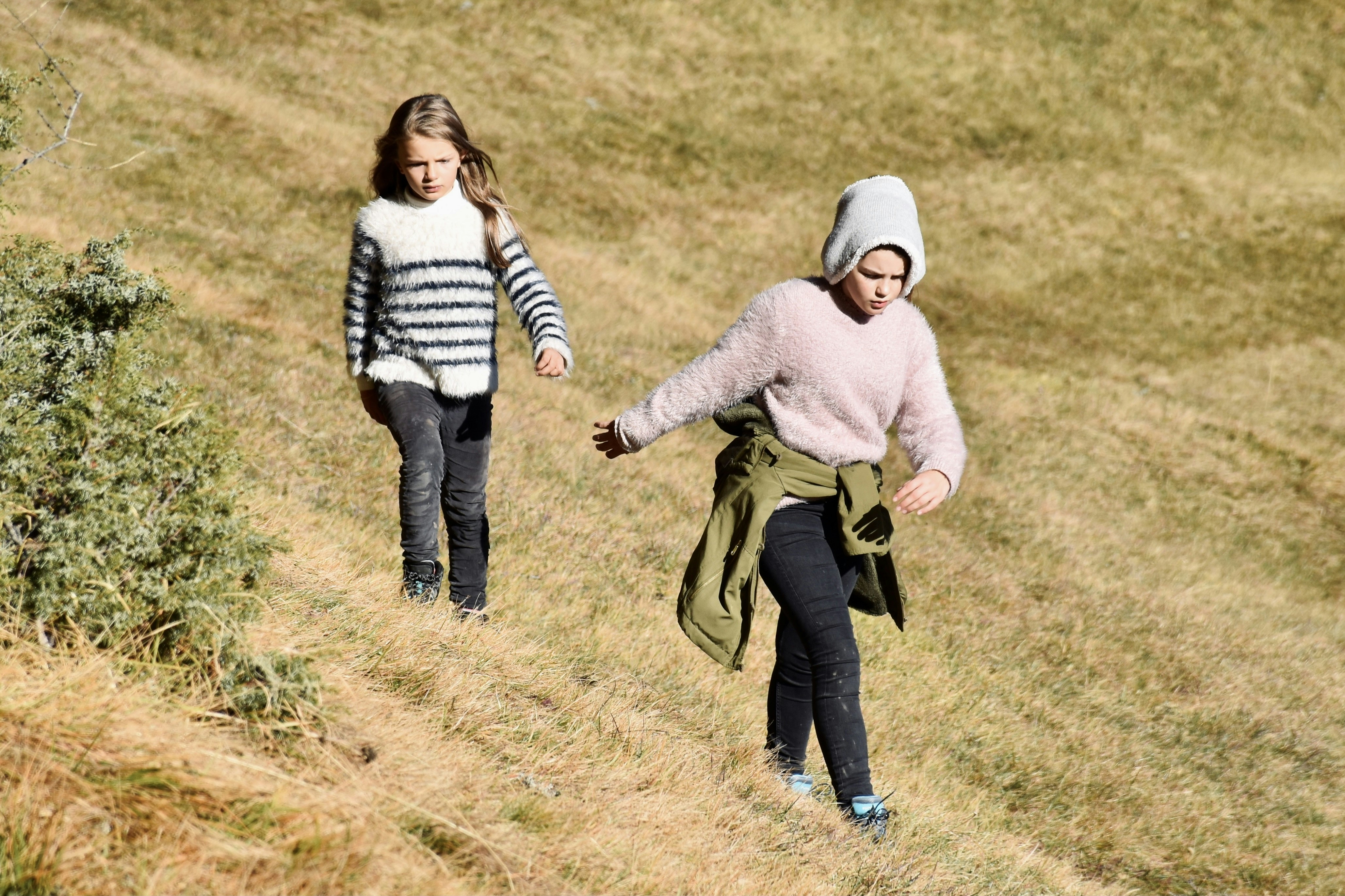 Two children stride across sunlit hillside, chasing the horizon
