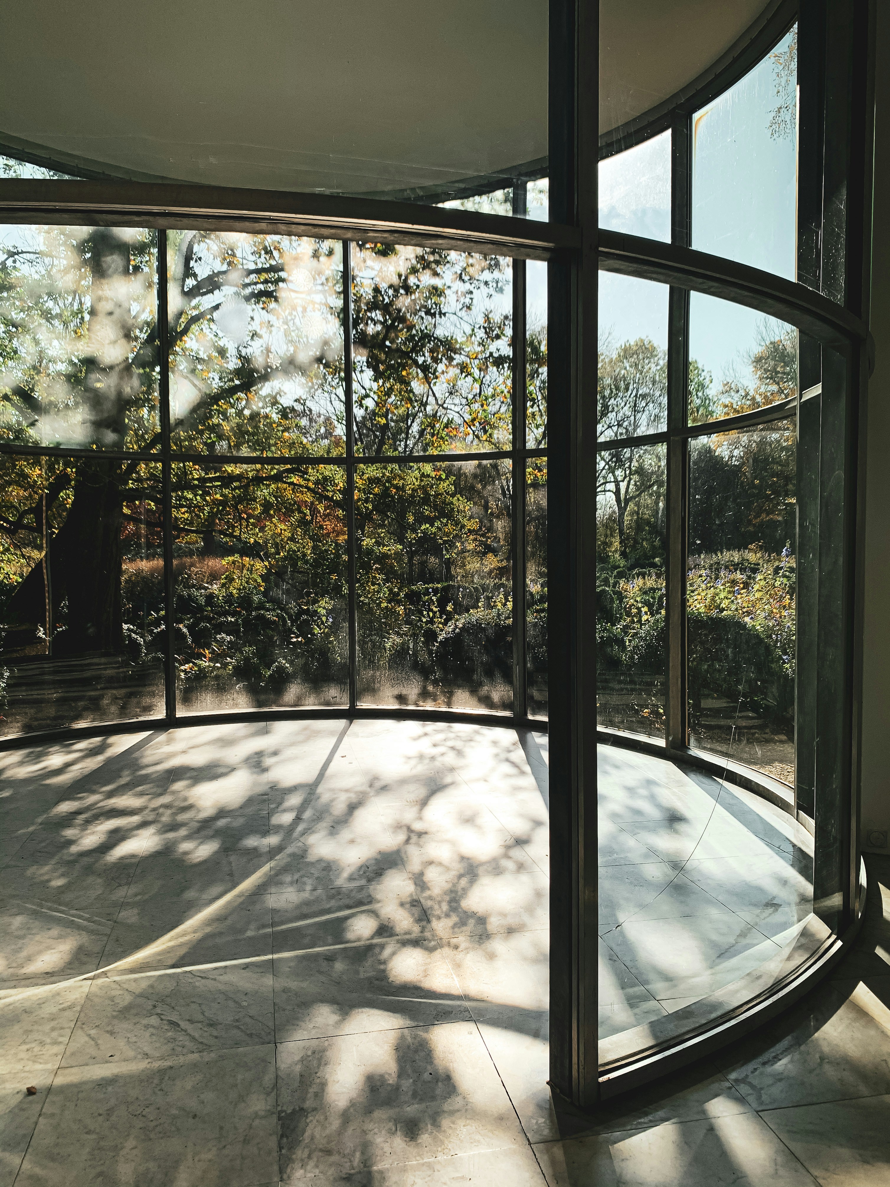 Glass Atrium with Curved Frames and Sunlit Terrace