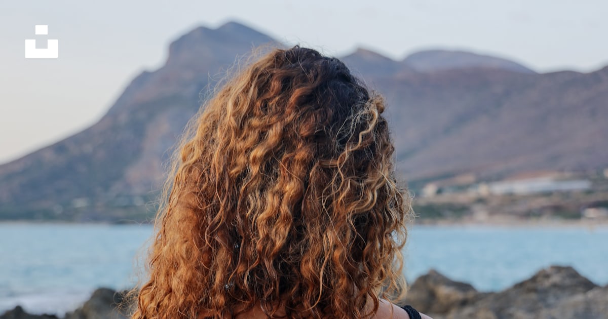 Woman In Black Bikini Sitting On Rock Near Sea During Daytime Photo