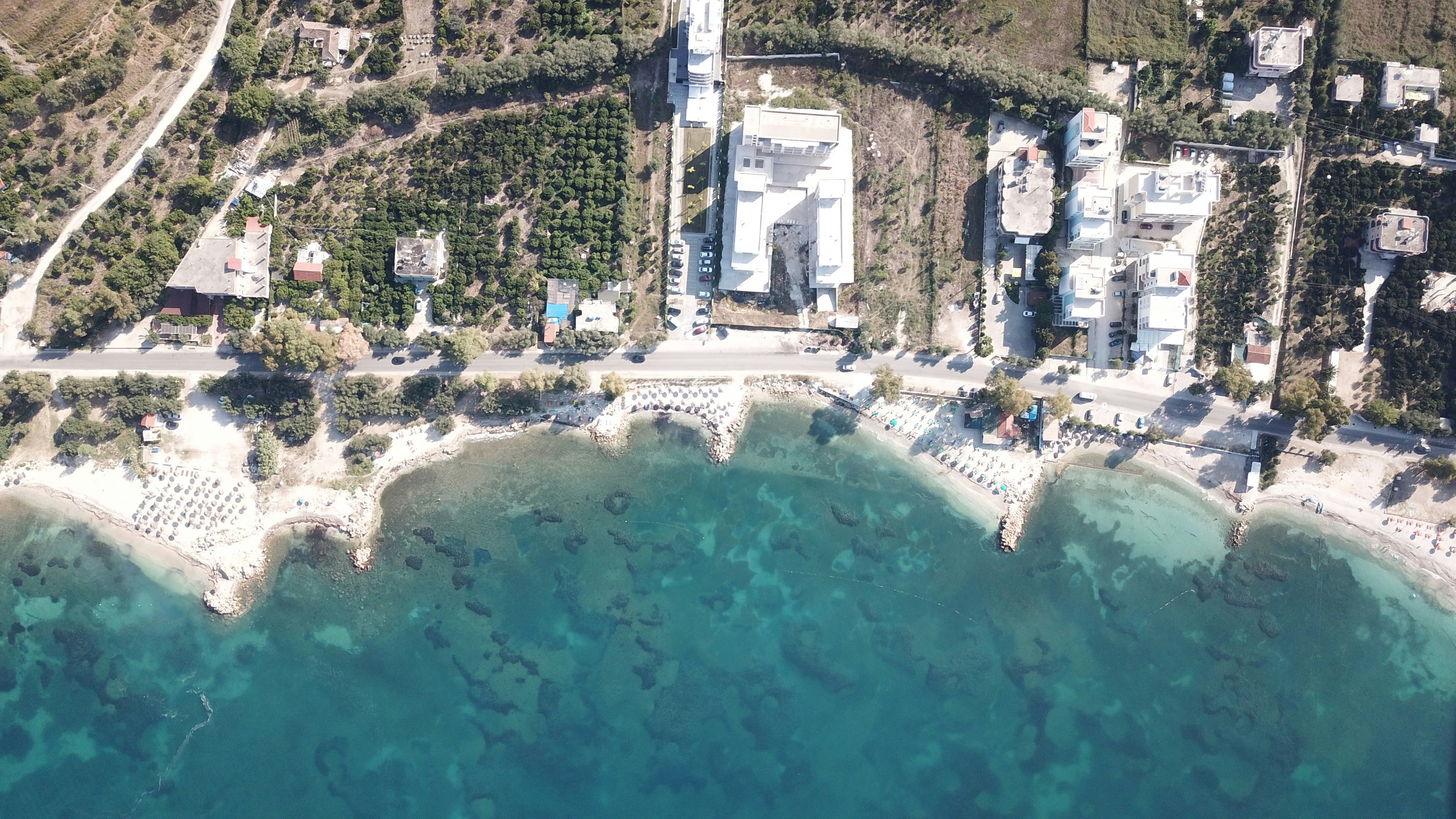 Aerial view of a serene coastline with turquoise waters and adjacent buildings.
