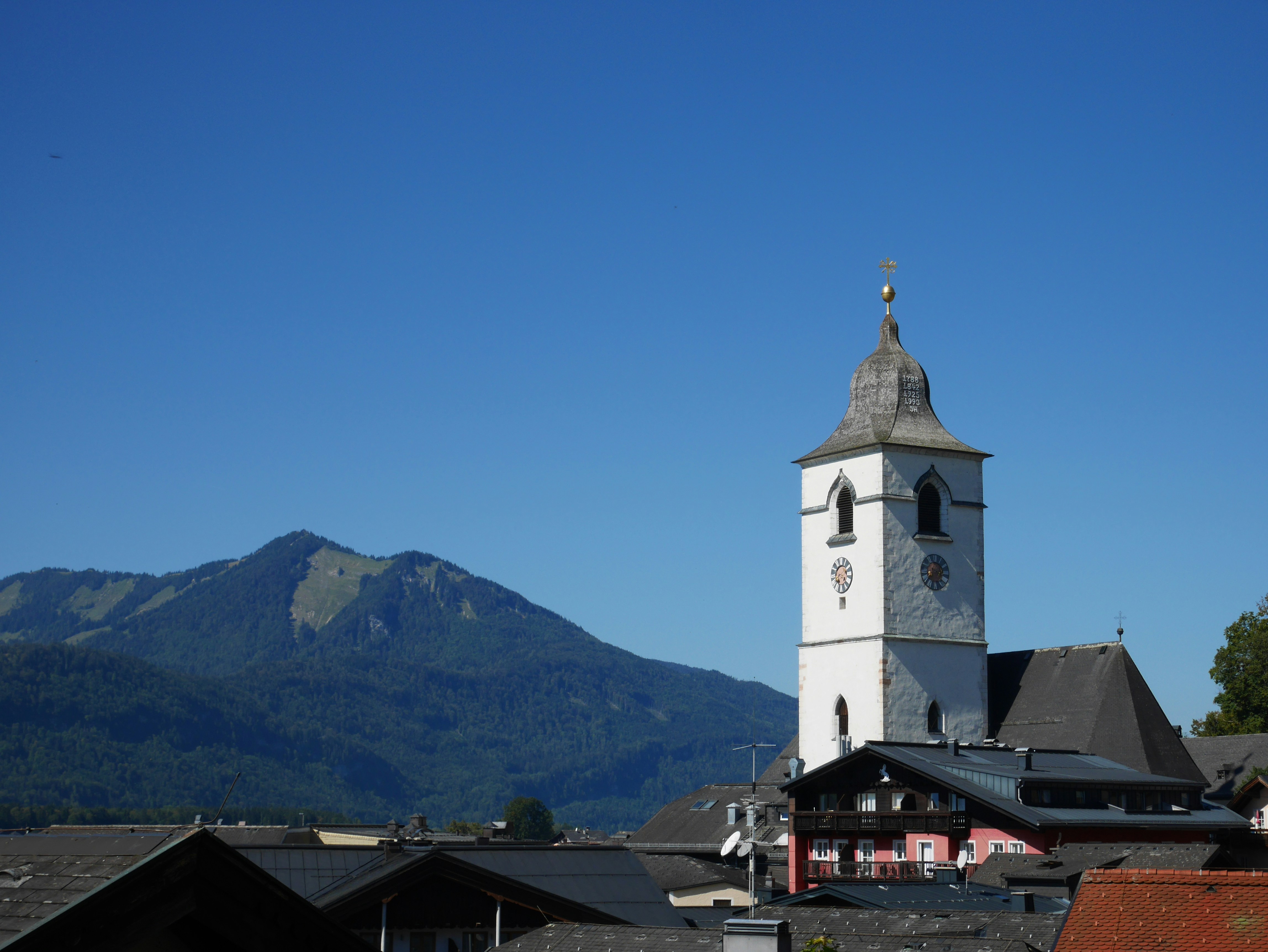 White church tower against a deep blue sky with mountains in the background.