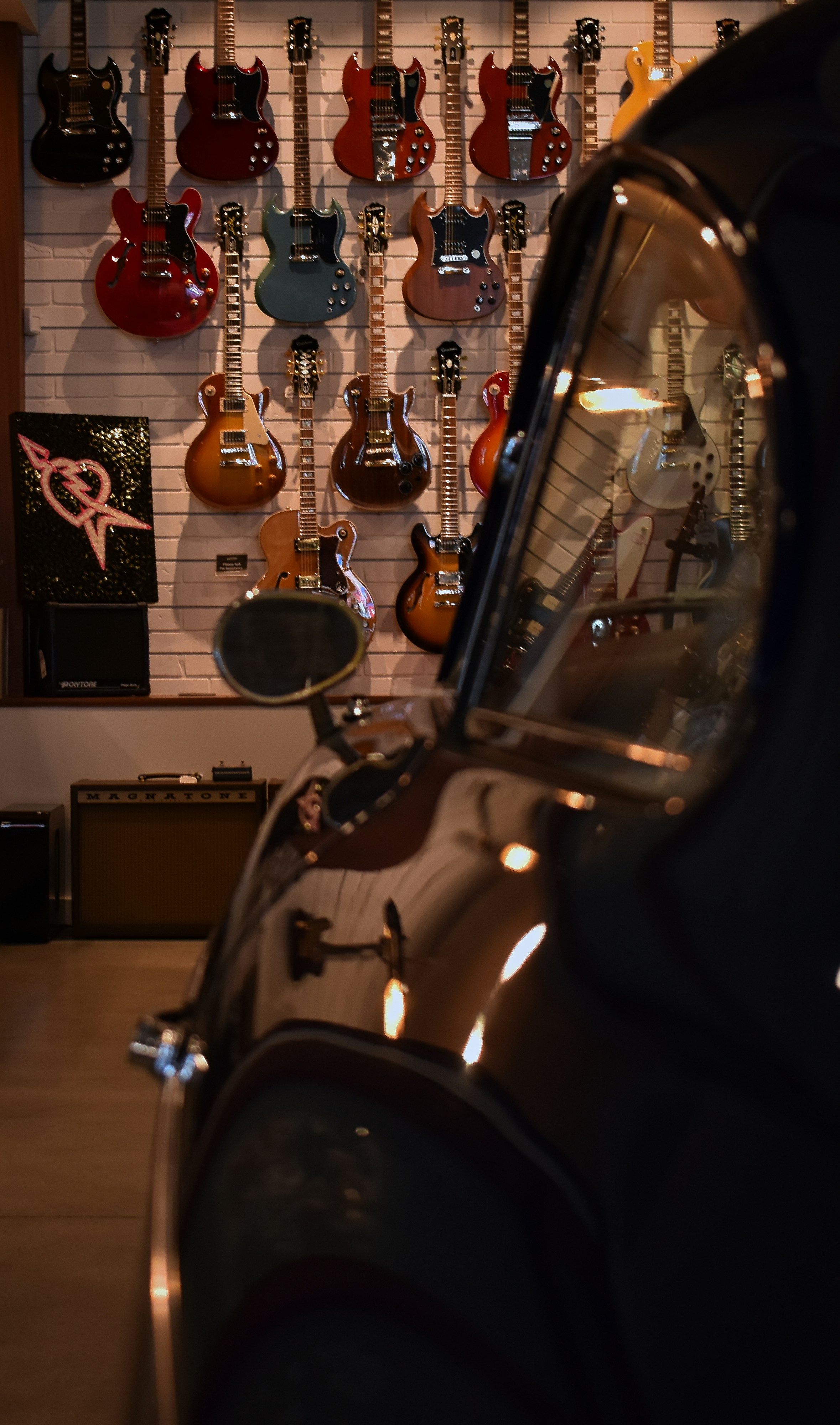 Guitar Display Behind a Chrome Car in a Guitar Shop Portrait