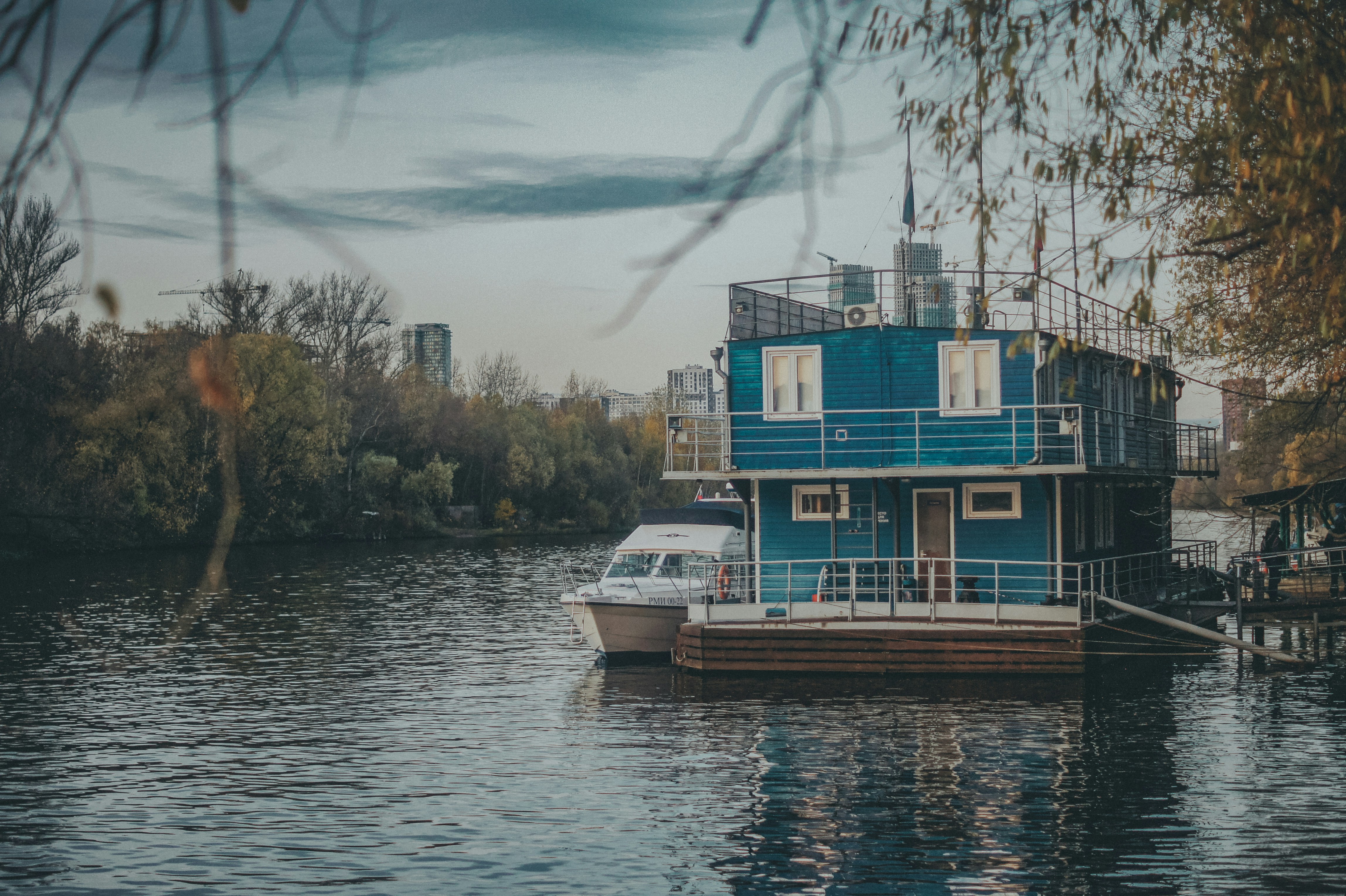 Twin-Deck Blue Houseboat Anchored Along a Quiet Riverside Bend