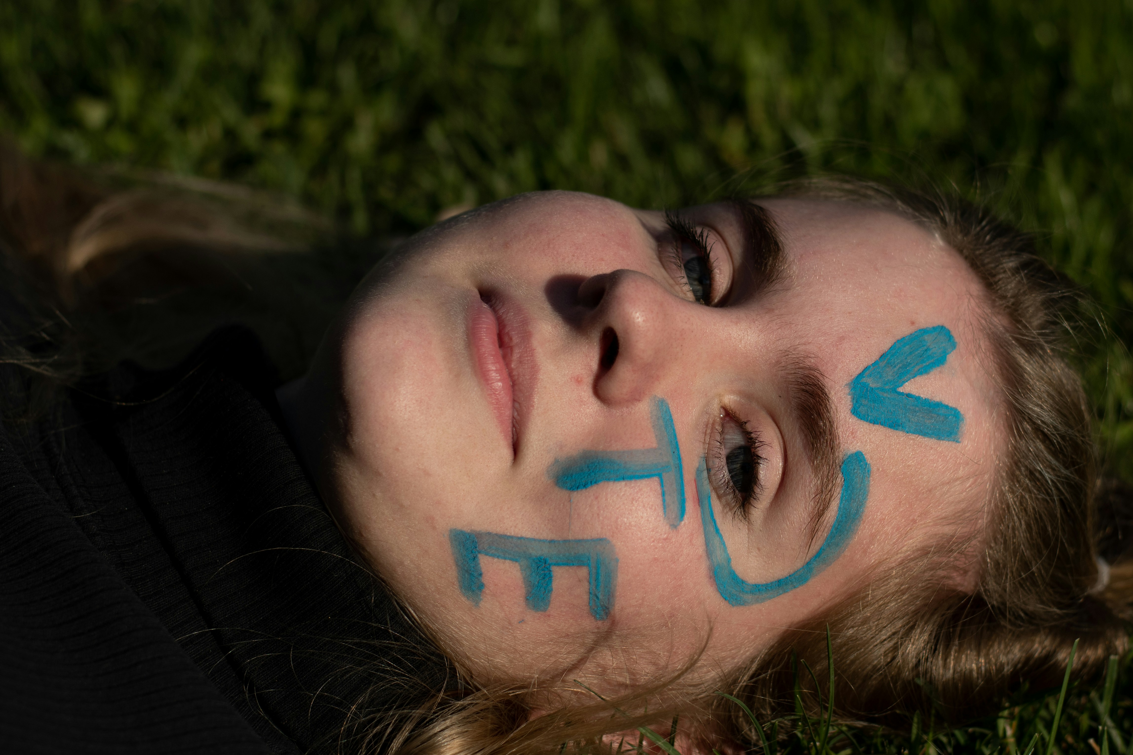 Blue LOVE on Grass: A Tilted Portrait with Painted Letters