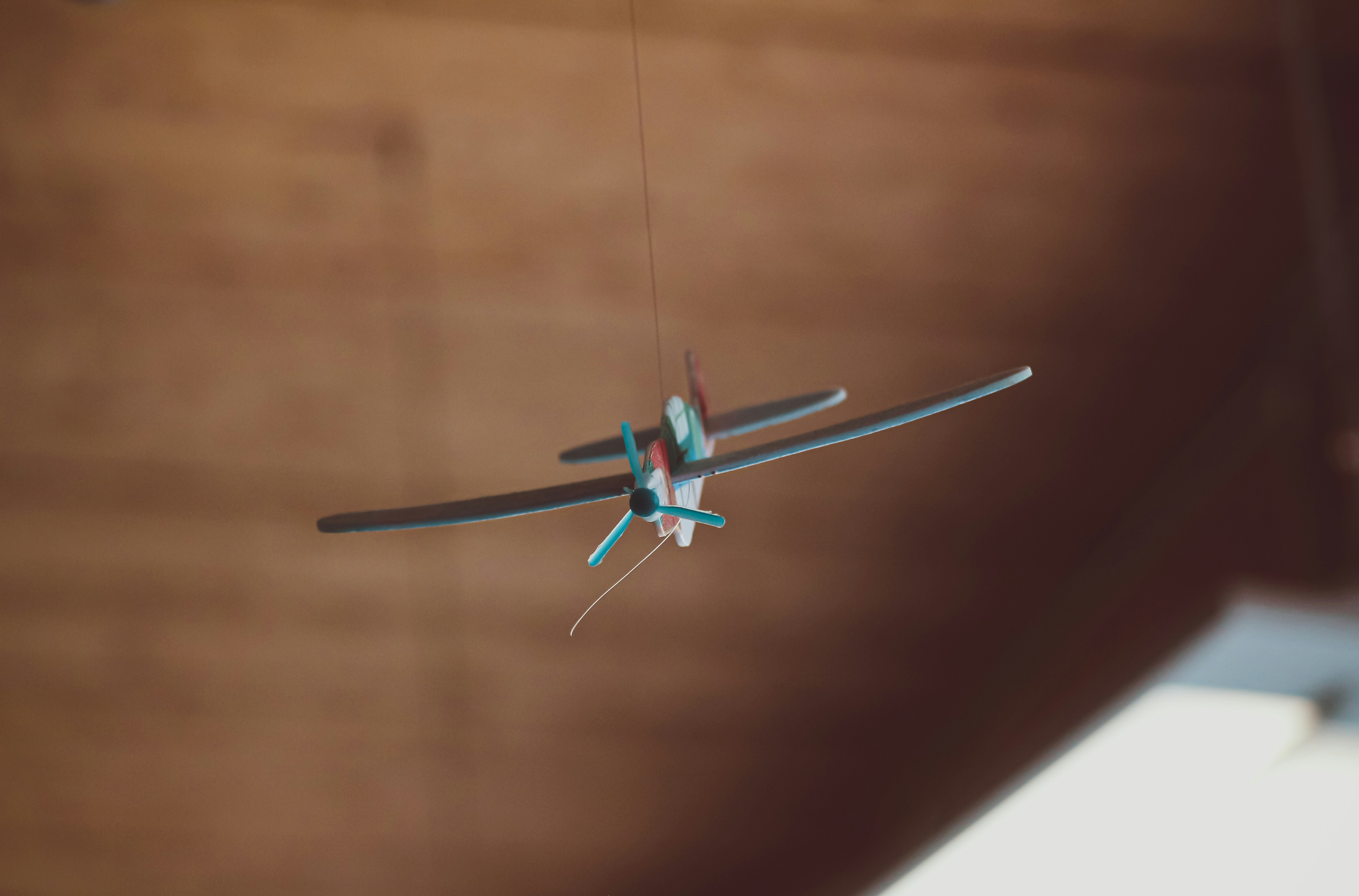 Teal Micro Glider Dangling Under a Wooden Ceiling