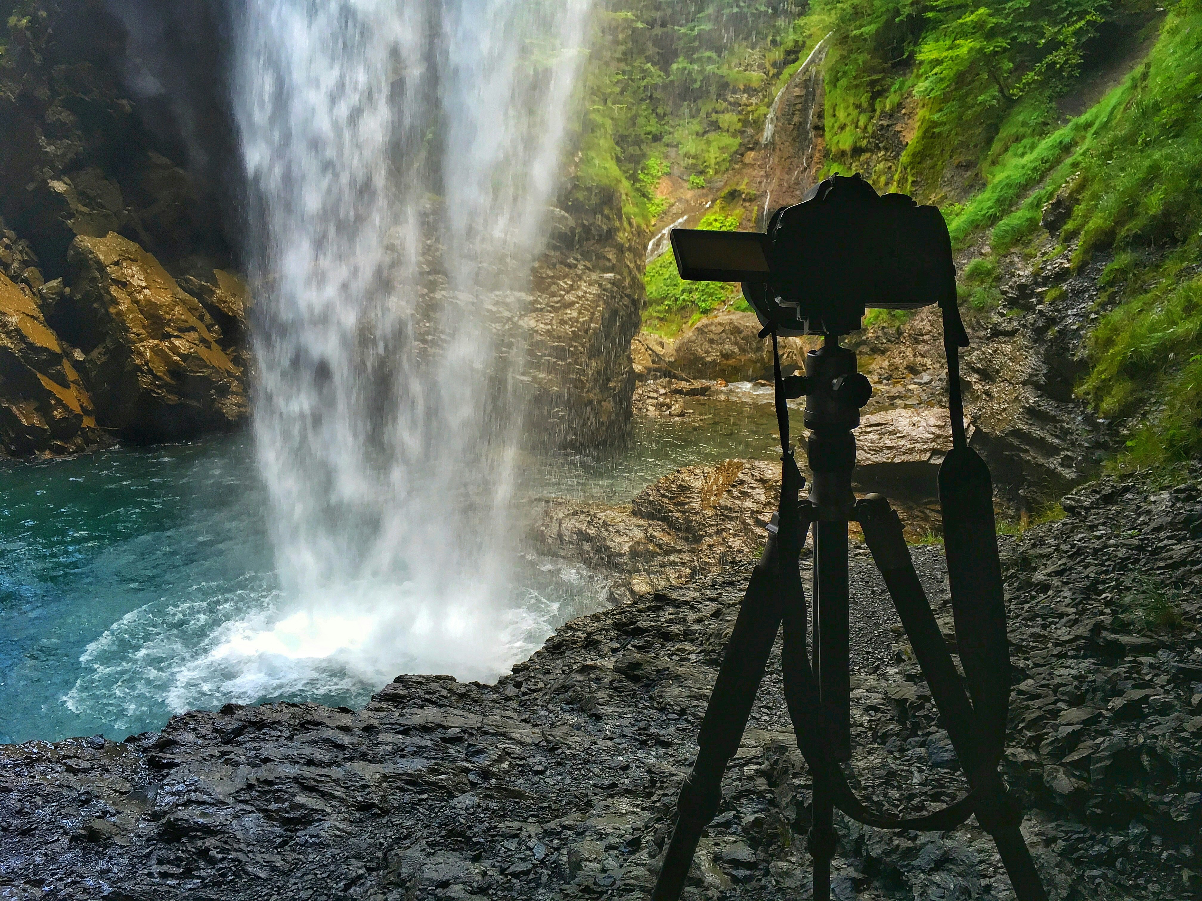 Black camera with tripod on rocky shore near waterfalls during daytime photo – Free Outdoor ...