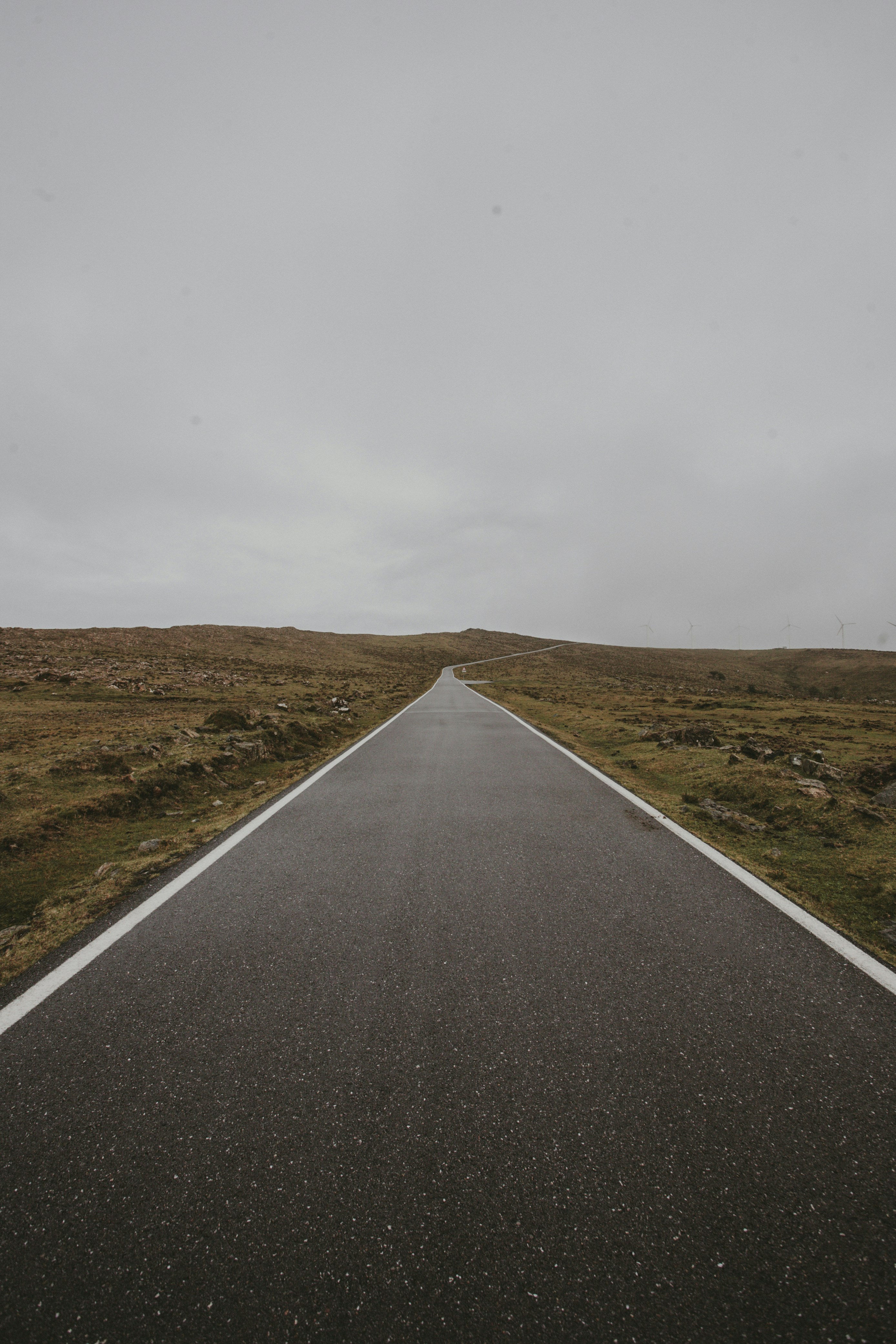 Gray asphalt road between green grass field under gray sky photo – Free Grey Image on Unsplash