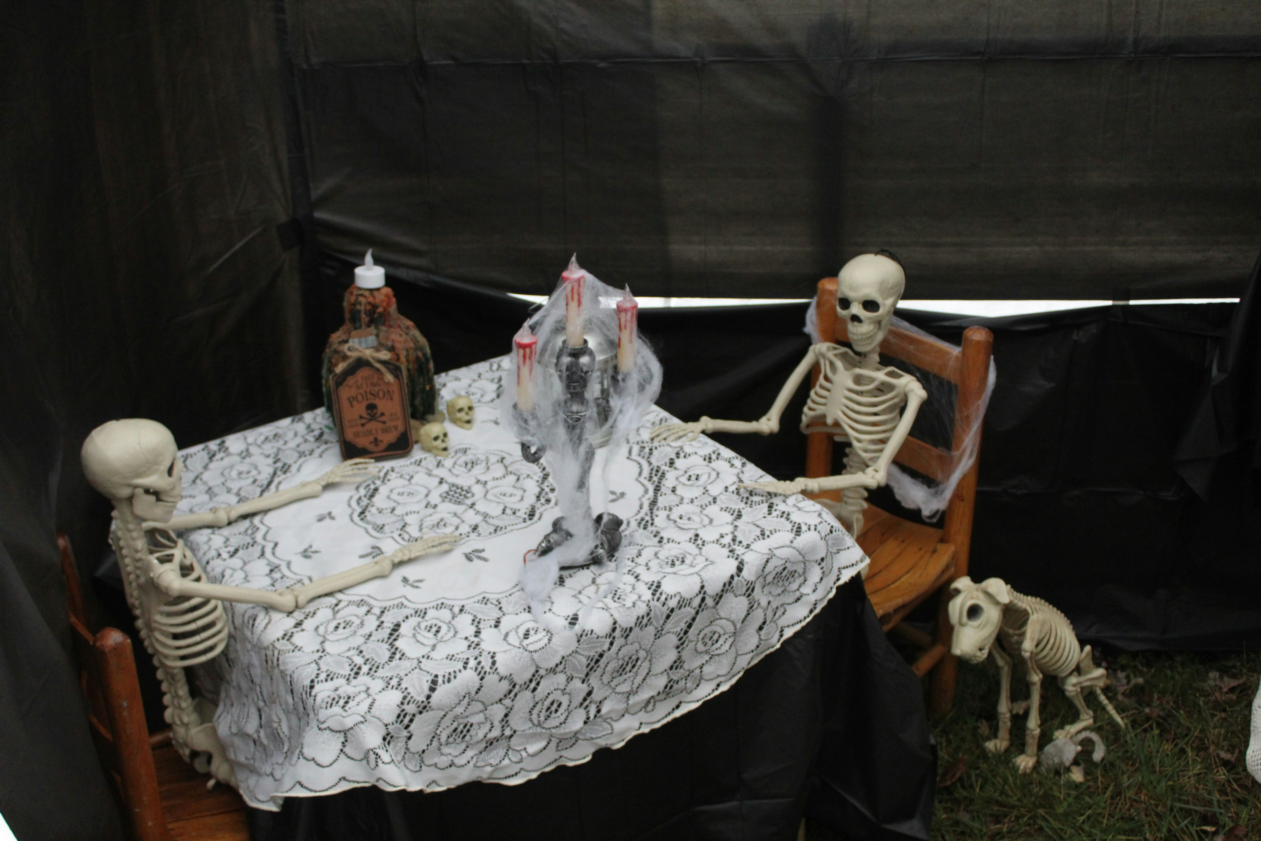 Veiled centerpiece at a lace-draped Halloween table with skeletal guests