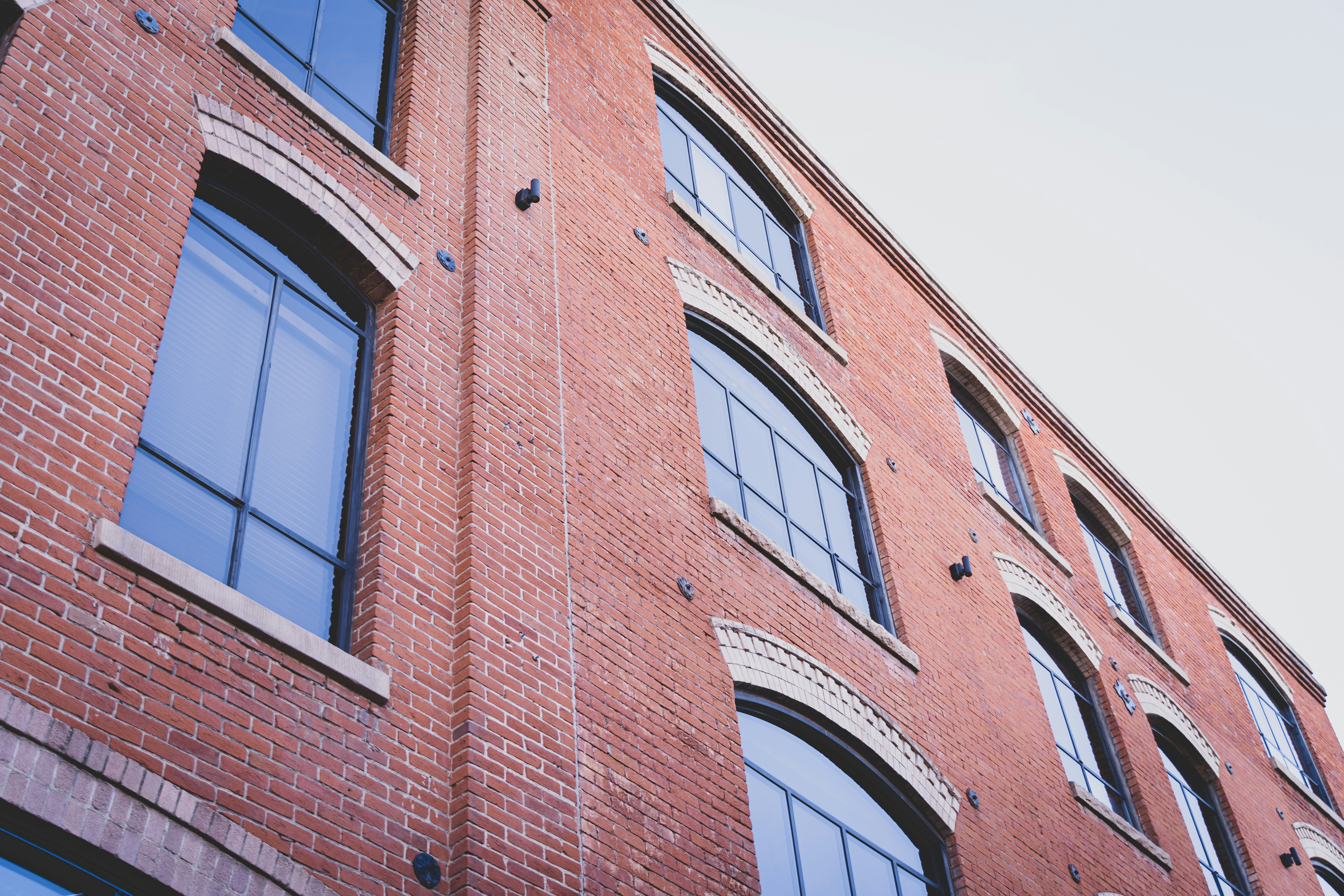 Tall brick building with large arched windows under a clear sky.