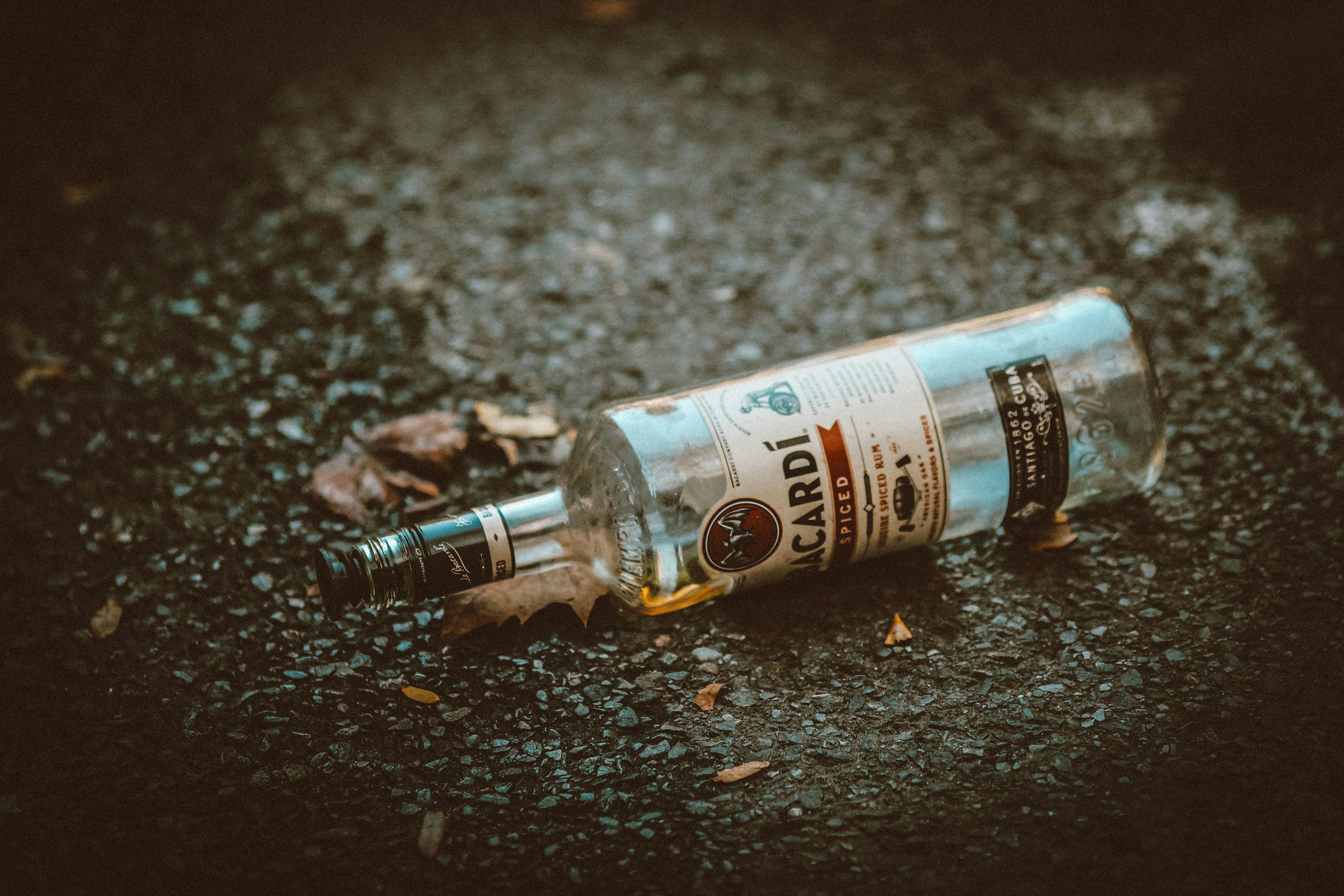 Discarded Bacardi Bottle on Rough Asphalt