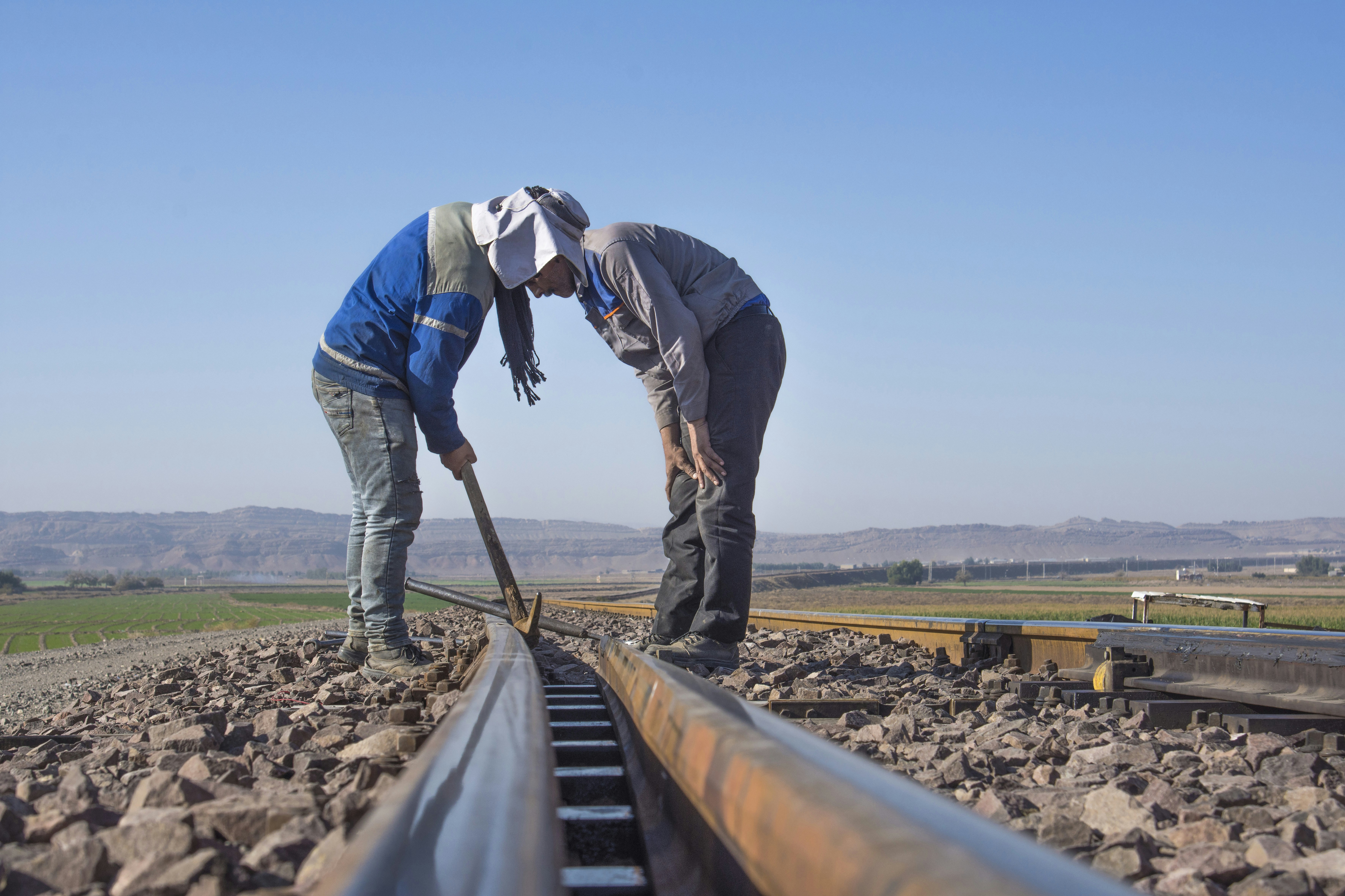 Man in blue jacket and black pants holding stick standing on train rail ...