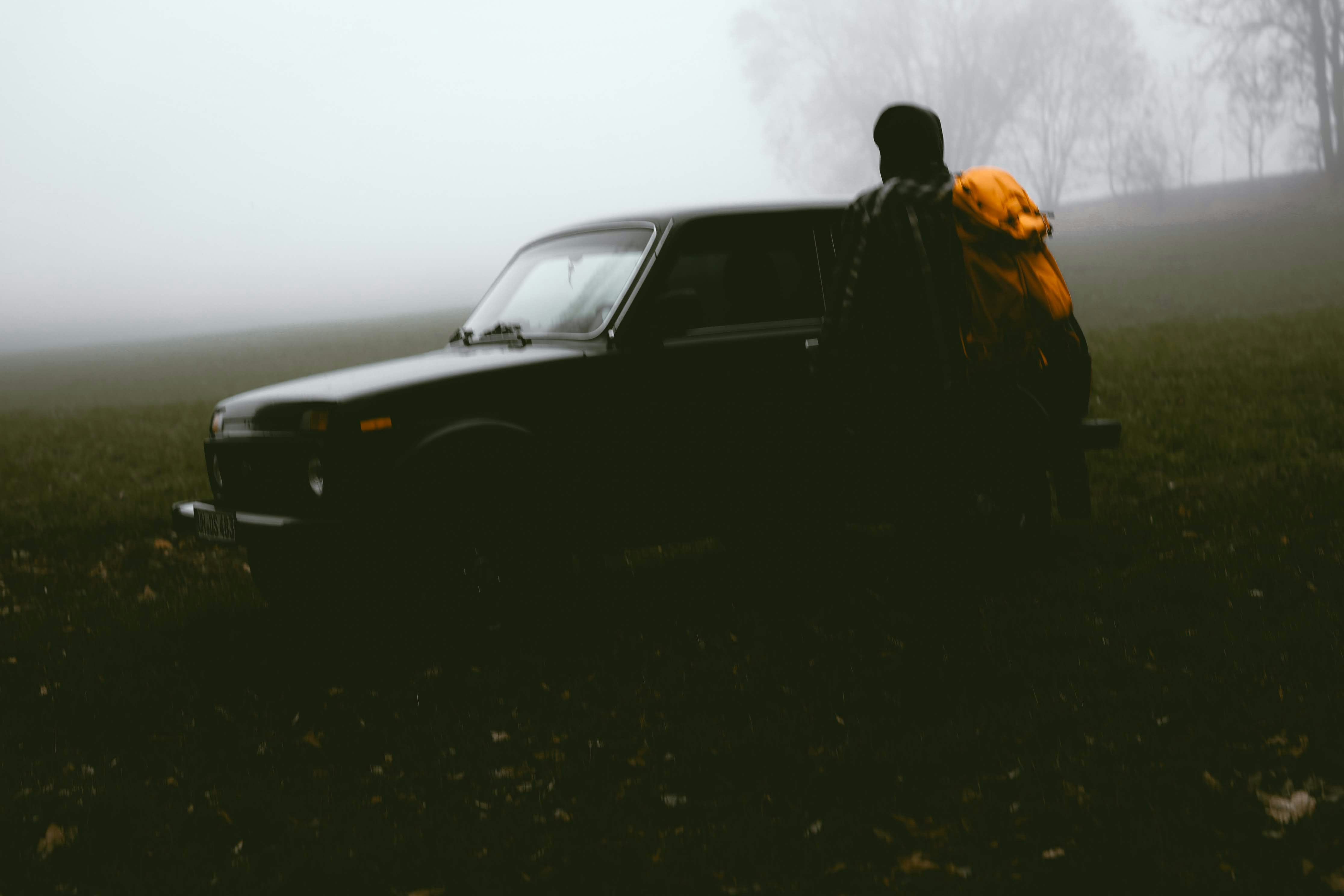 Venture in the Fog: A Vintage Sedan Meets an Orange-Backpacked Stranger