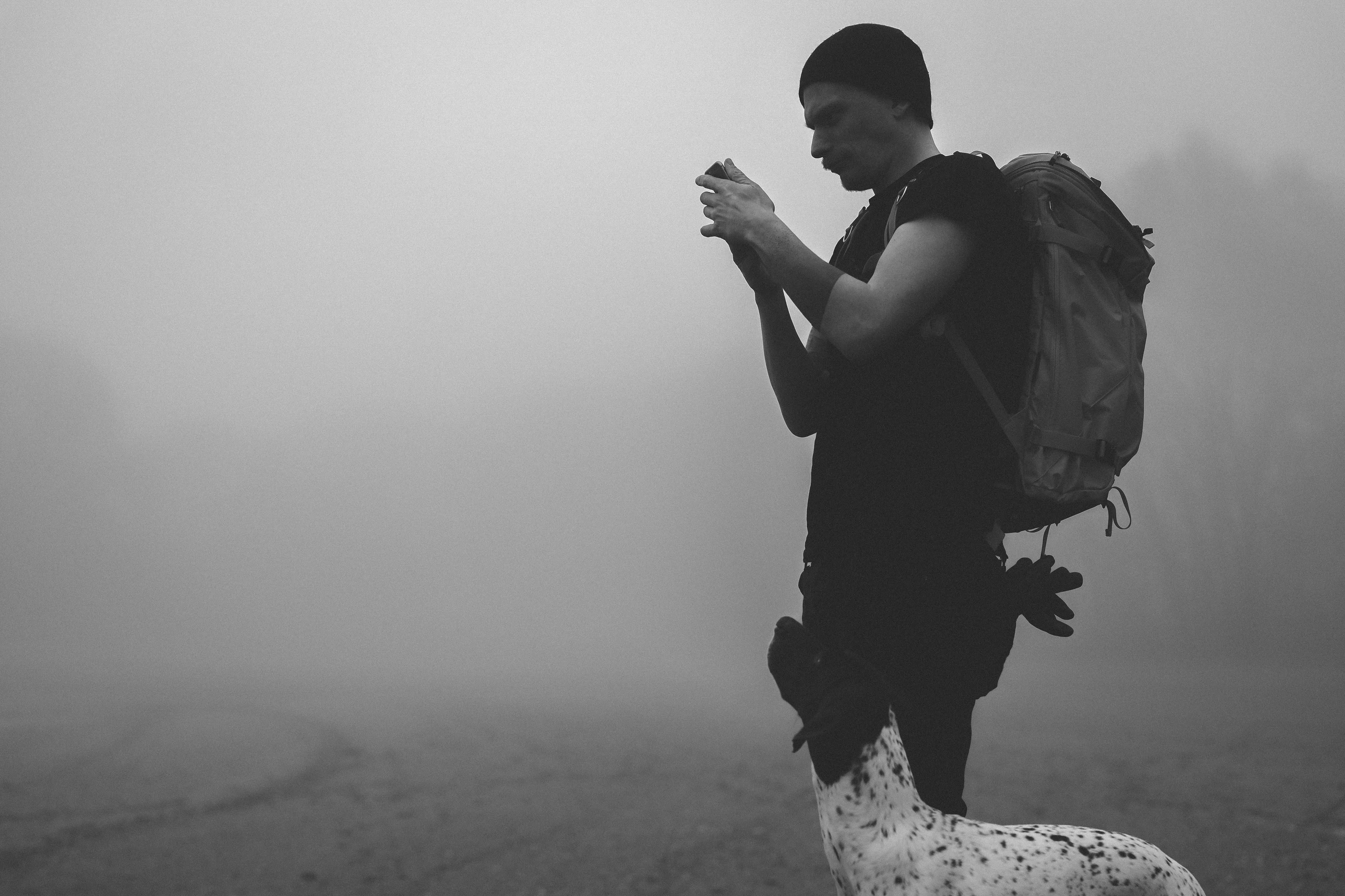 Mistbound Moment: A man with a backpack and a Dalmatian in fog