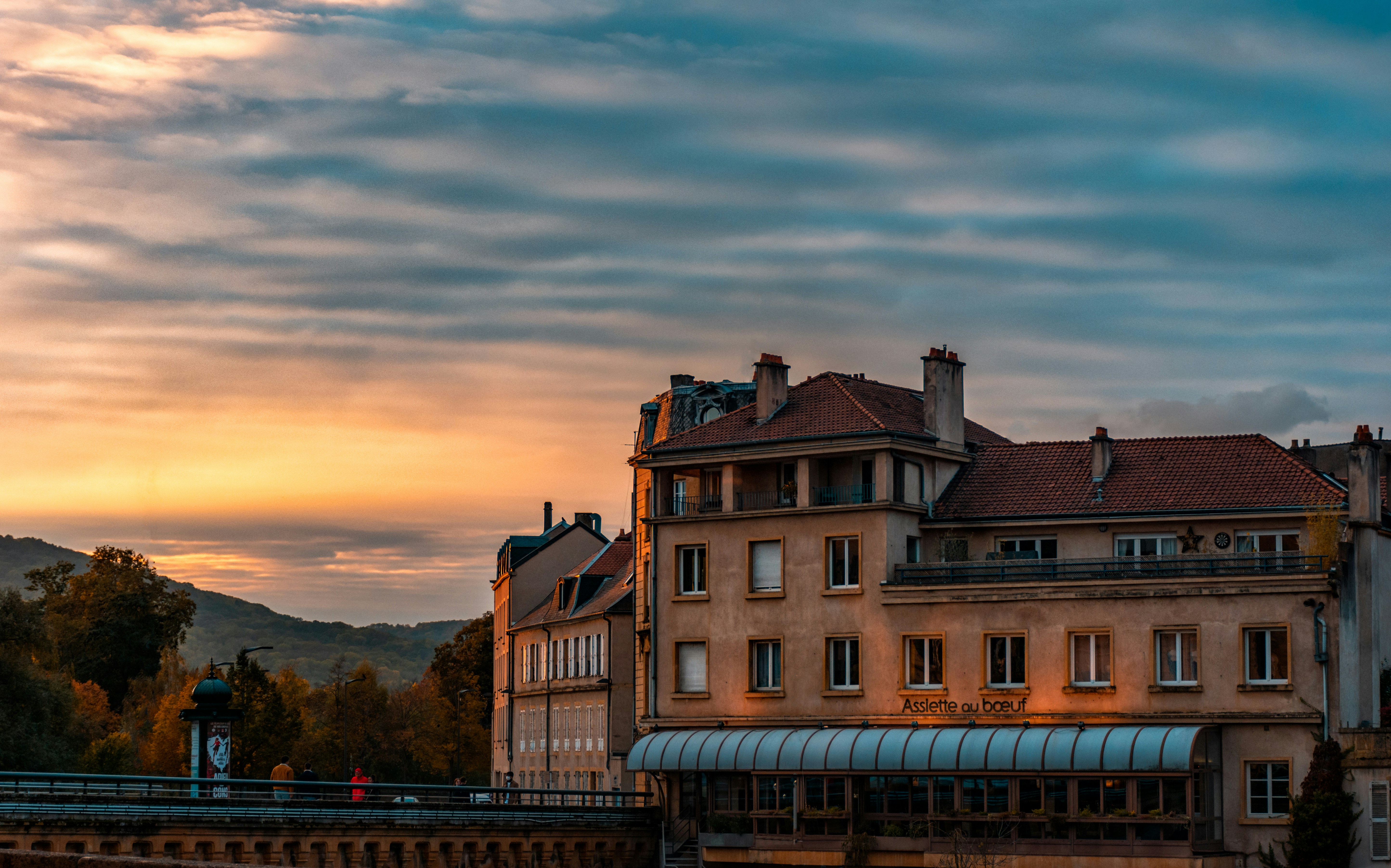 Historic building by a river at sunset with vibrant clouds.
