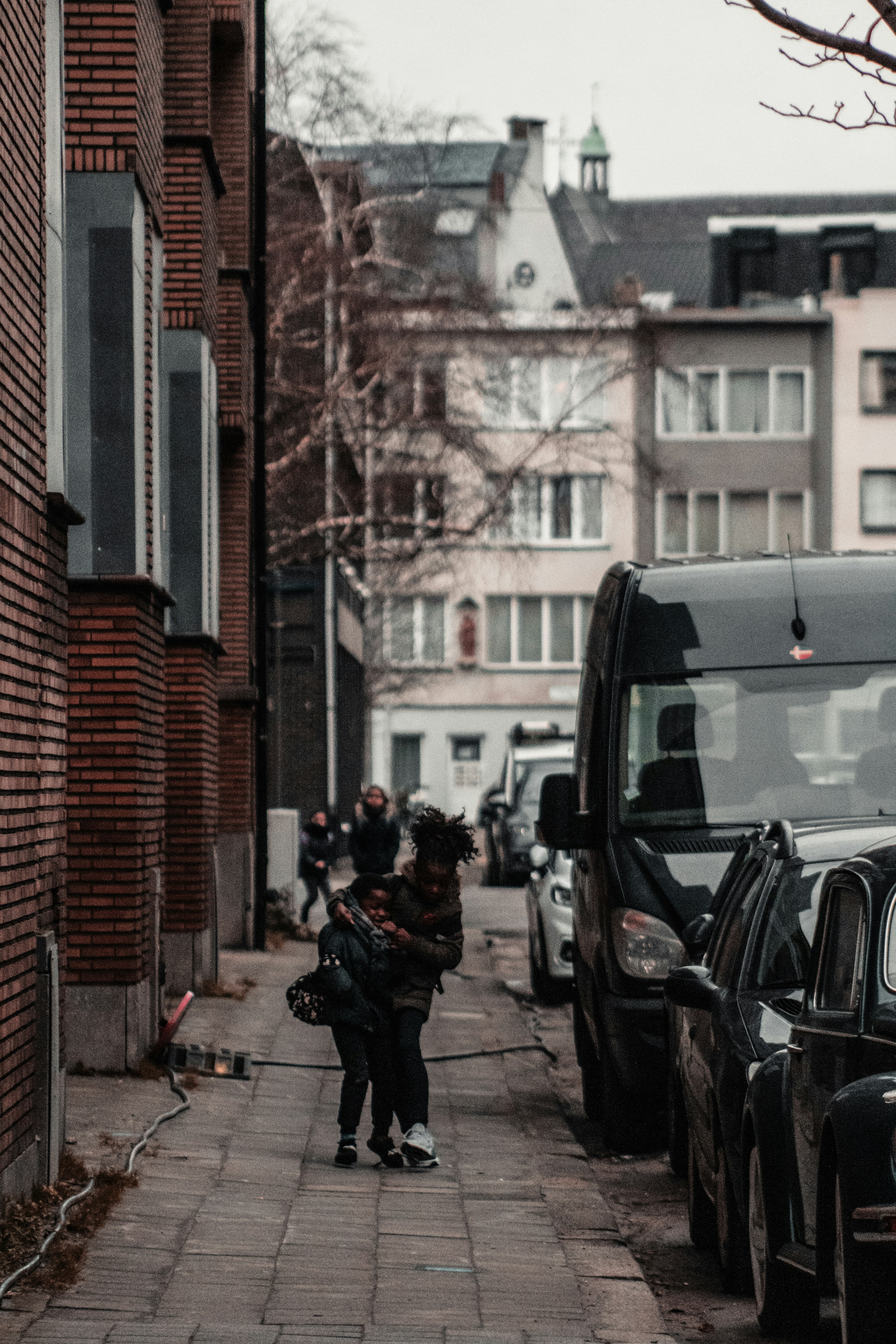 Two Friends Share a Stolen Moment on a Narrow City Street