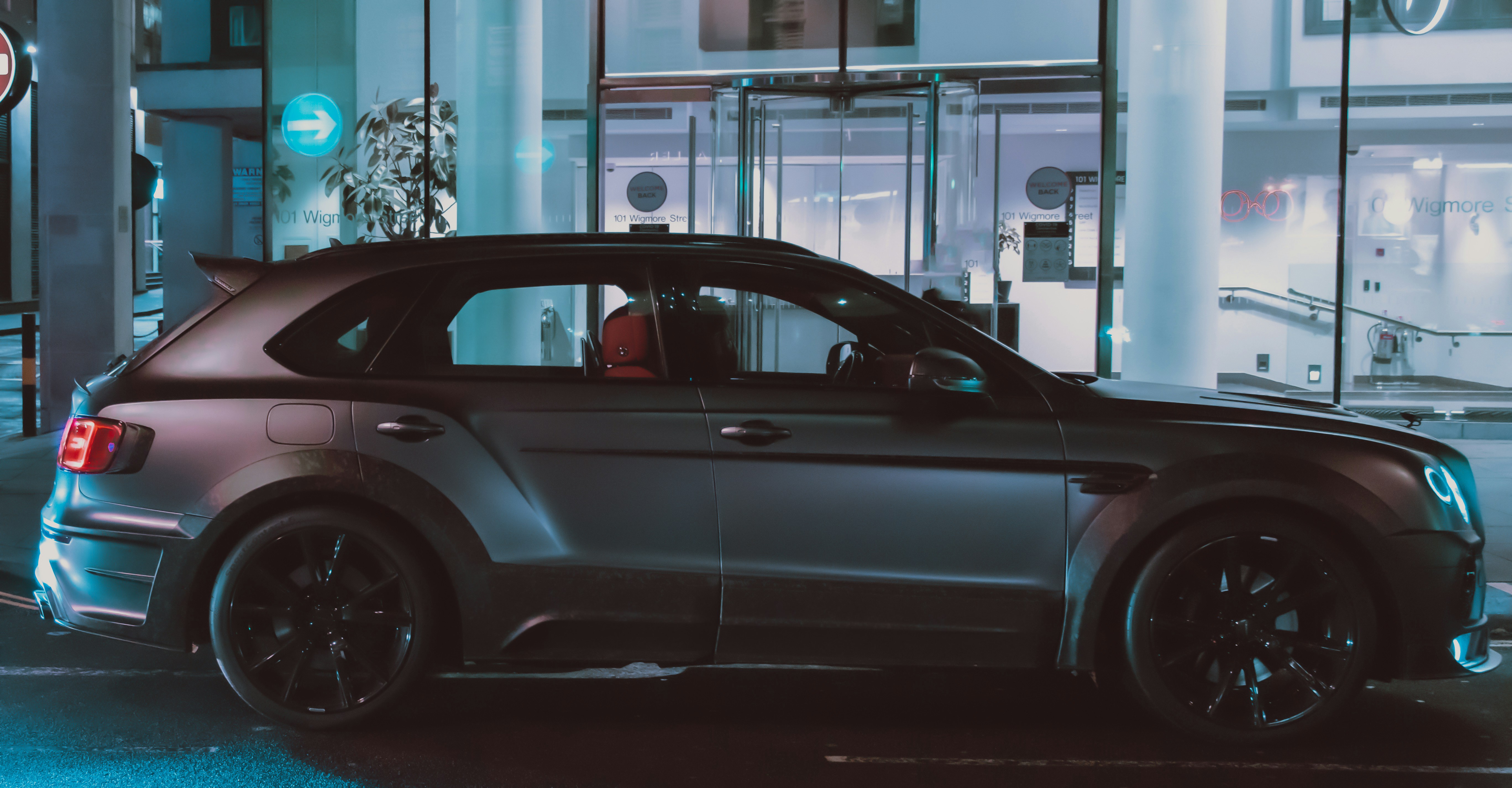 Sleek black SUV parked under city lights with modern glass buildings in the background.