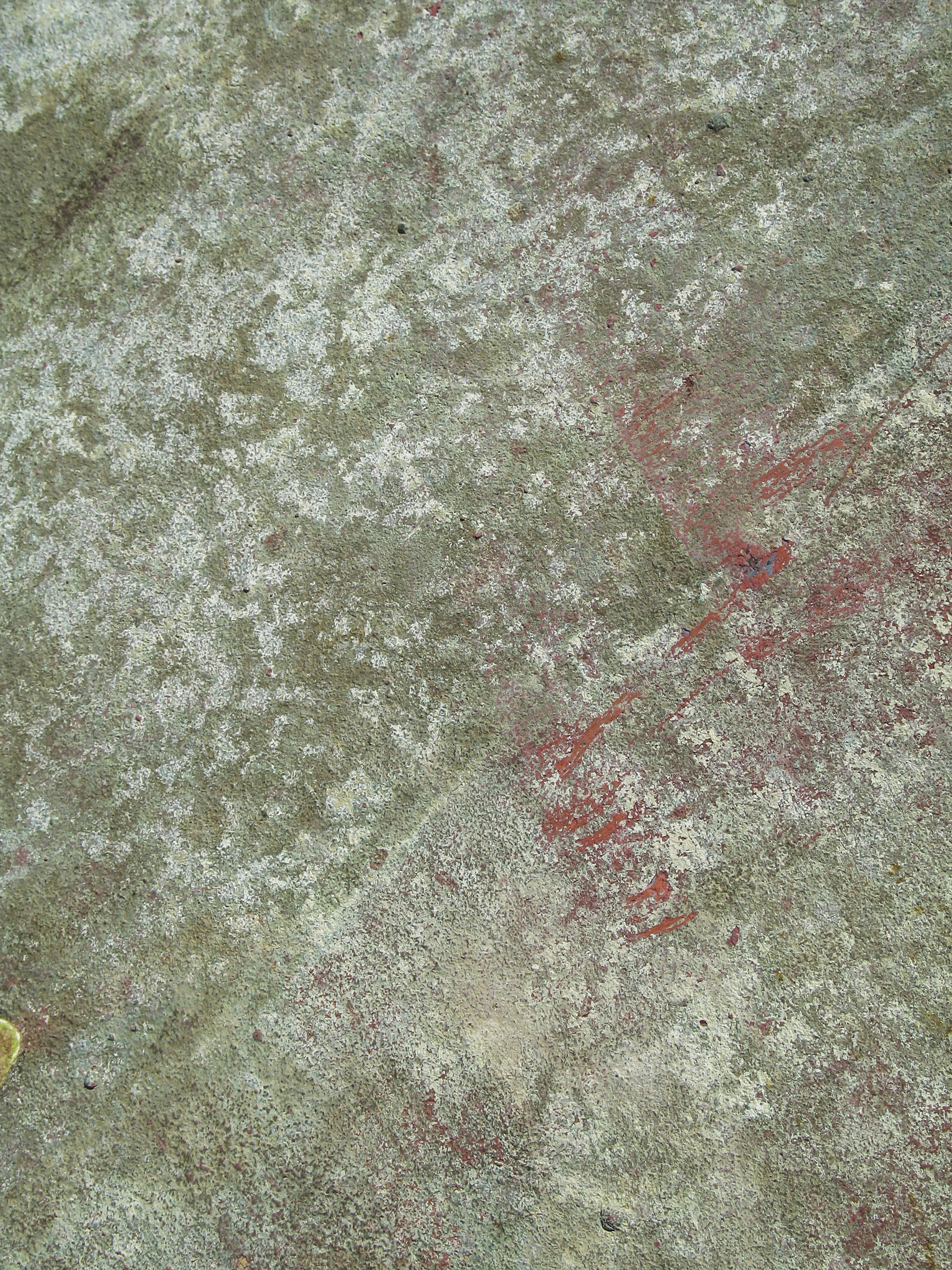 Close-up of weathered rock surface accented with red chalk scratches, emphasizing texture and color. The rugged markings invite inspection of surface detail.