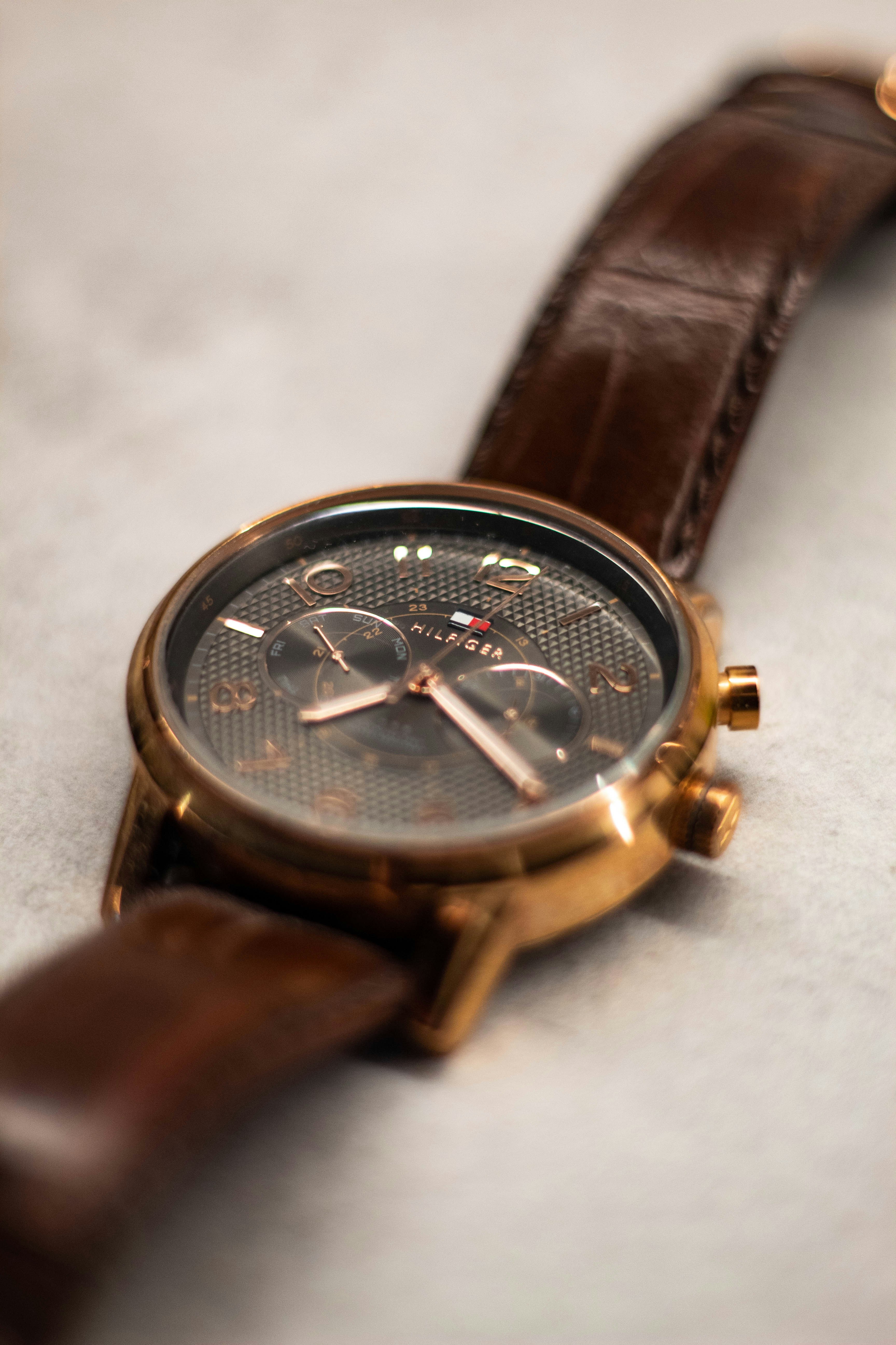 Close-up of a stylish watch featuring a textured black dial and brown leather strap. The intricate details highlight its craftsmanship.