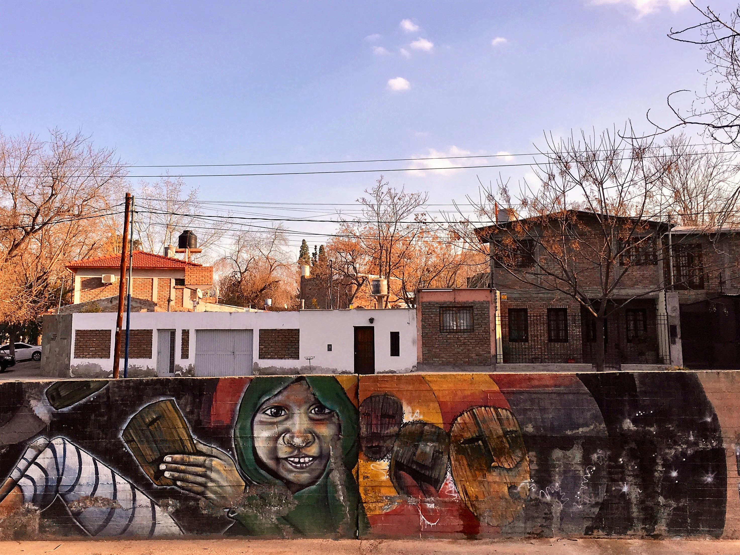 Vibrant mural depicting diverse characters on a brick wall beneath a clear sky.