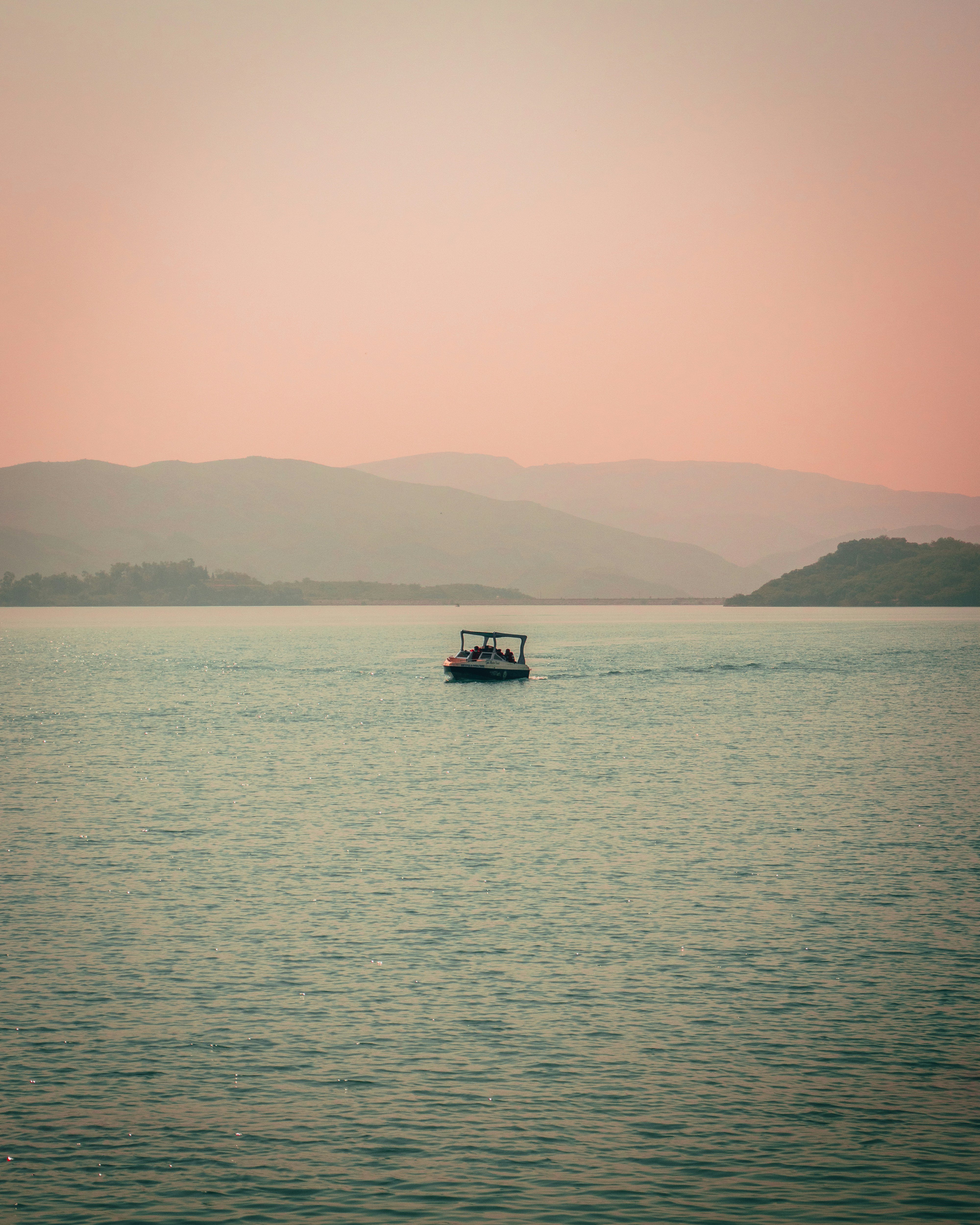 Amber Hour: A solitary boat on velvet water under pastel skies