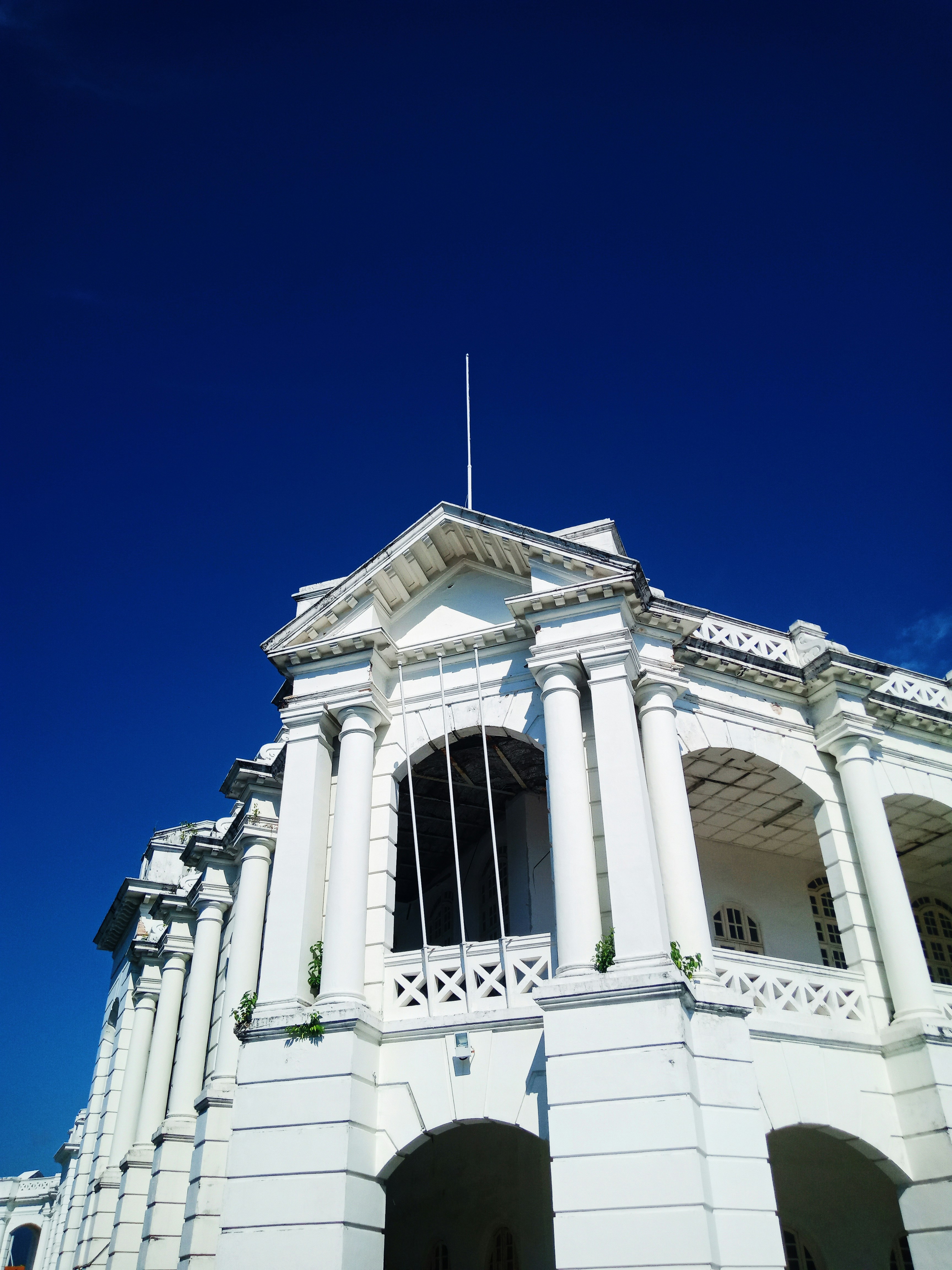 Historic colonial building with grand columns and a clear blue sky backdrop. The architecture showcases intricate details and a sense of timeless elegance.