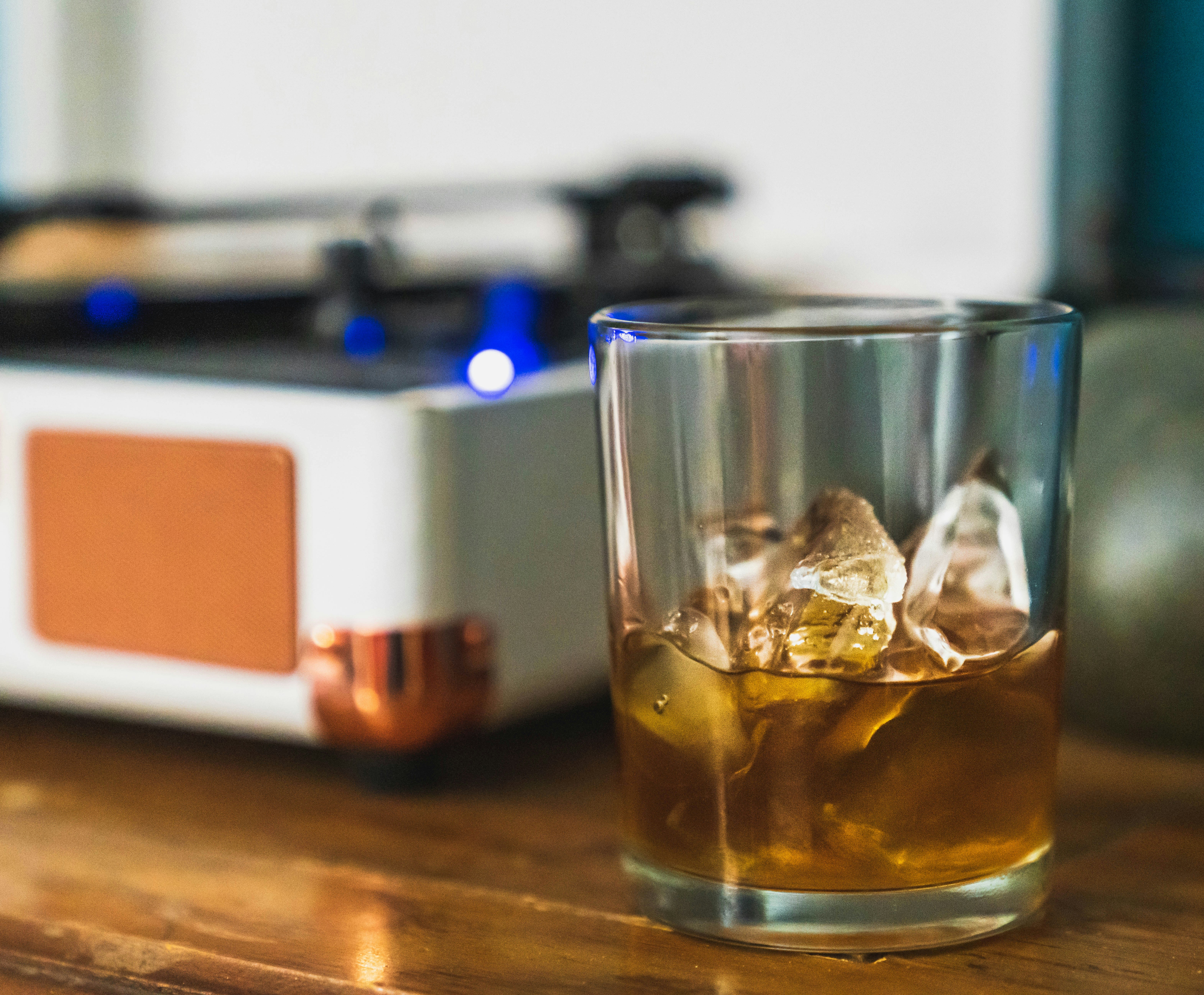 Glass of amber on a wooden bar with a retro turntable blur