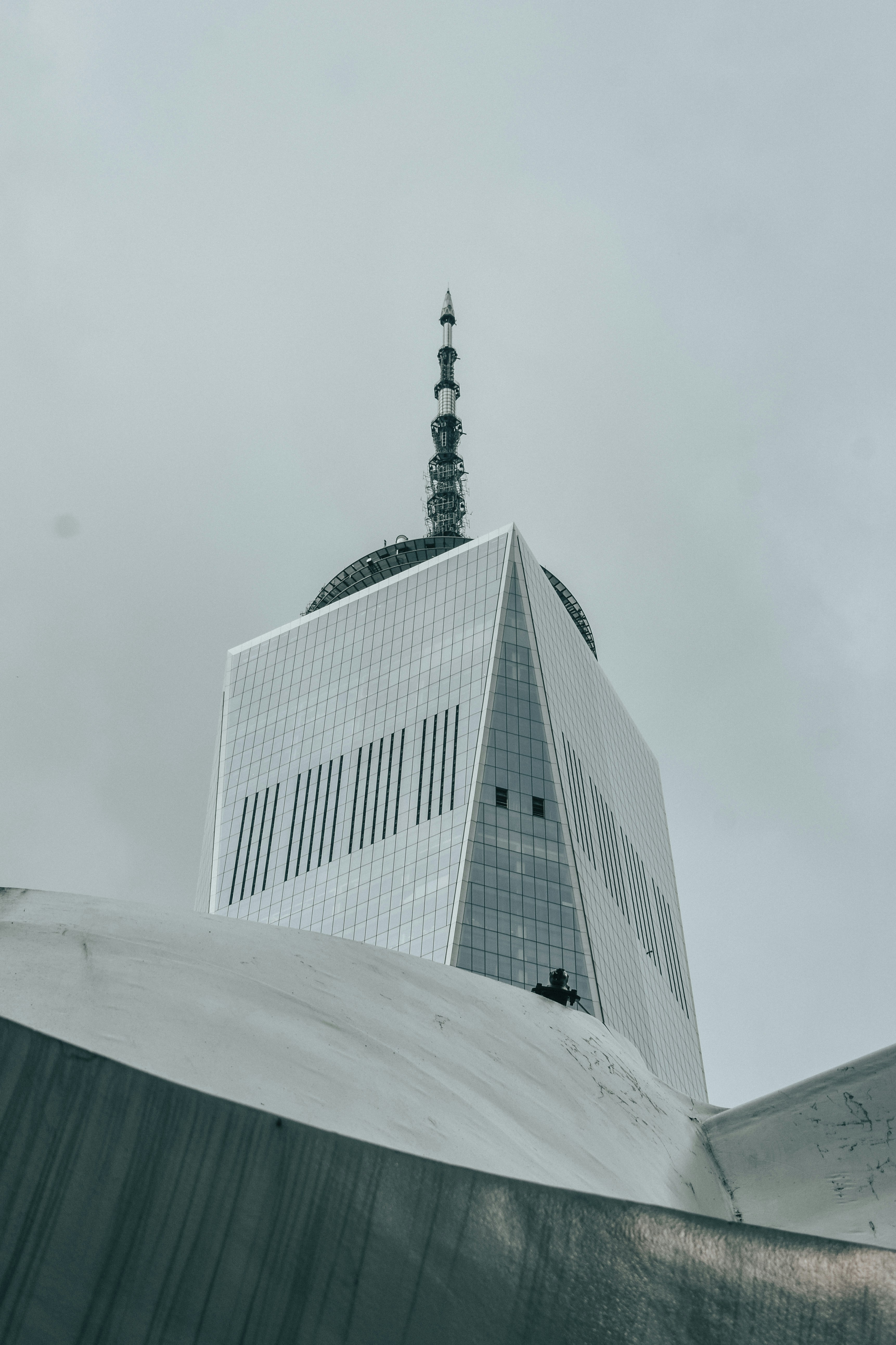 The towering structure showcases sleek lines and reflective glass, framed against a moody sky. An architectural feat that embodies contemporary design.