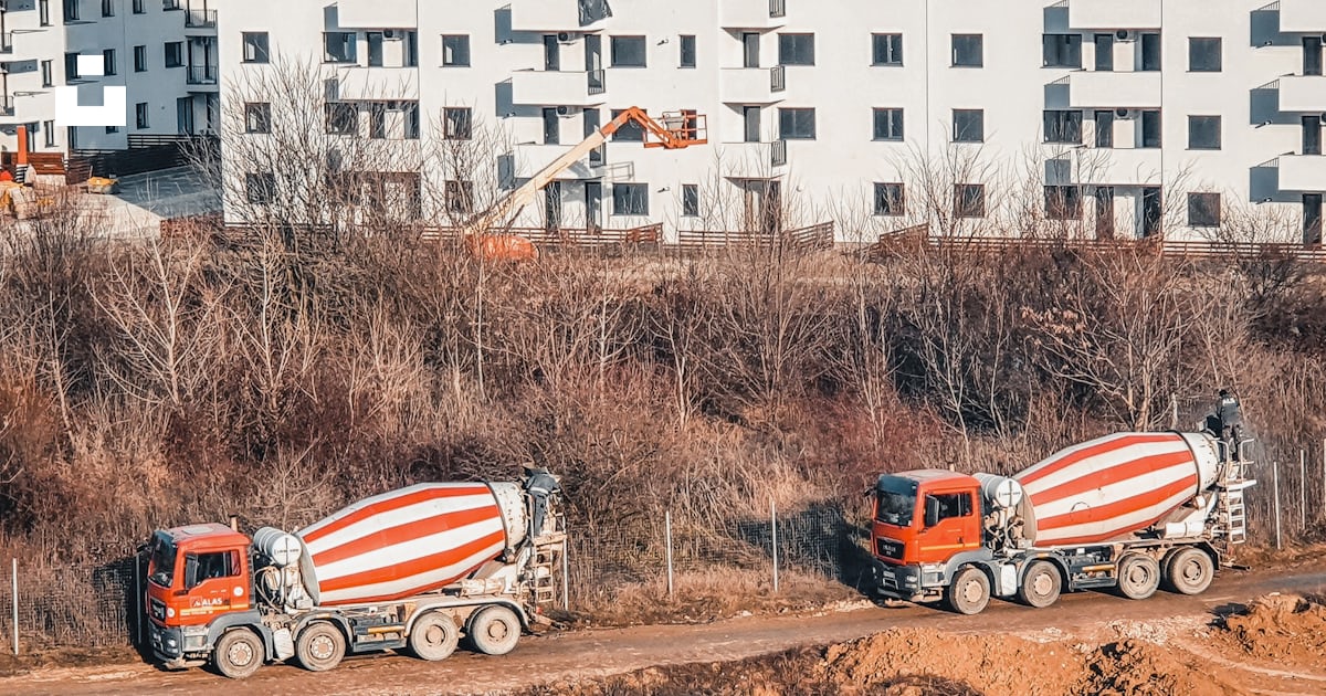 낮 동안 흰색 콘크리트 건물 근처의 갈색 필드에 빨간색과 흰색 빈티지 자동차 사진 Unsplash의 무료 건물 이미지