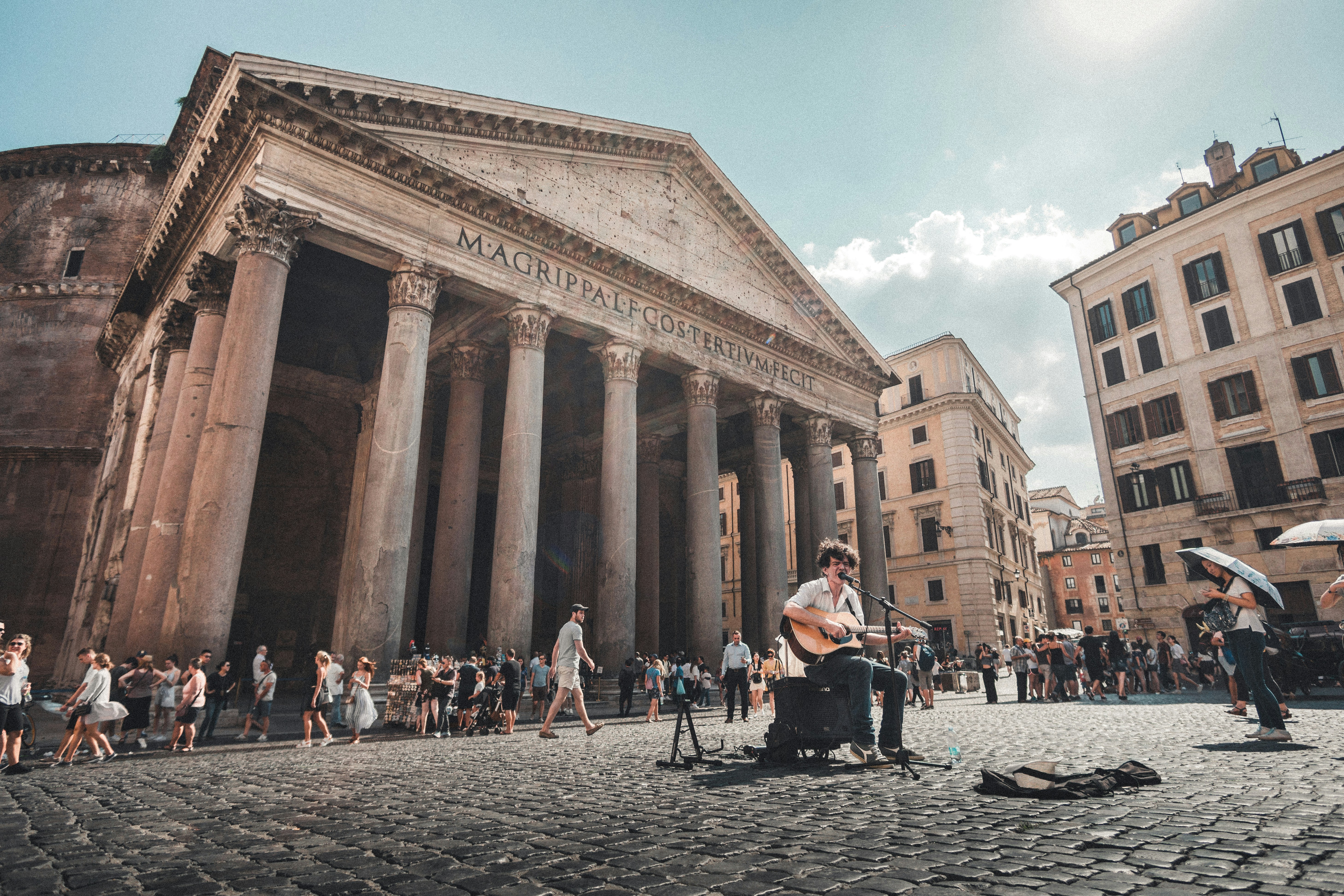 Street musician performing in front of the historic Pantheon, surrounded by an audience enjoying the lively atmosphere.