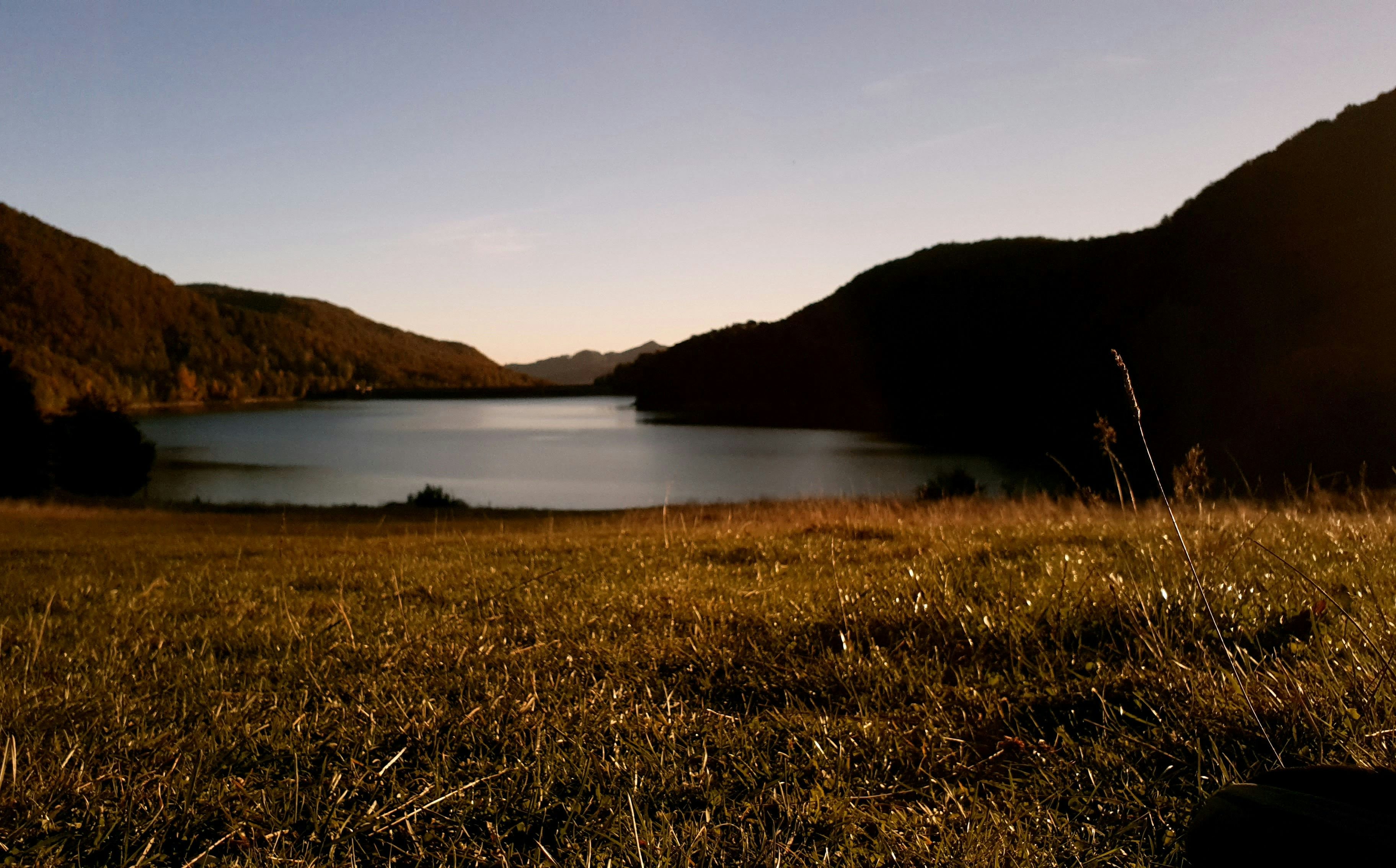Horizon in Gold: Grass, Lake, and Hills at Dusk