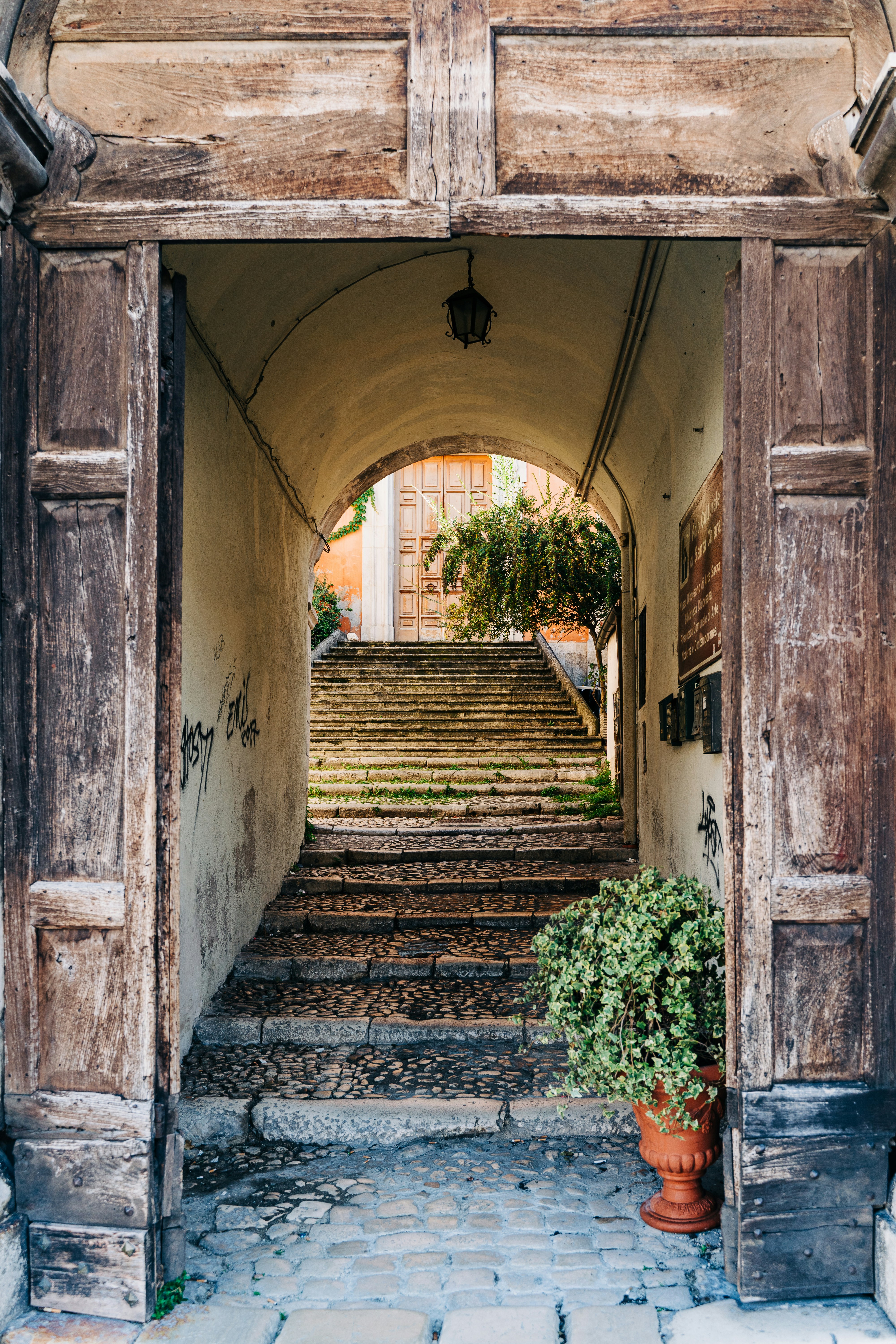 An old fashioned doorway in Sulmona, Abruzzo, Italy | brown wooden staircase between white concrete walls