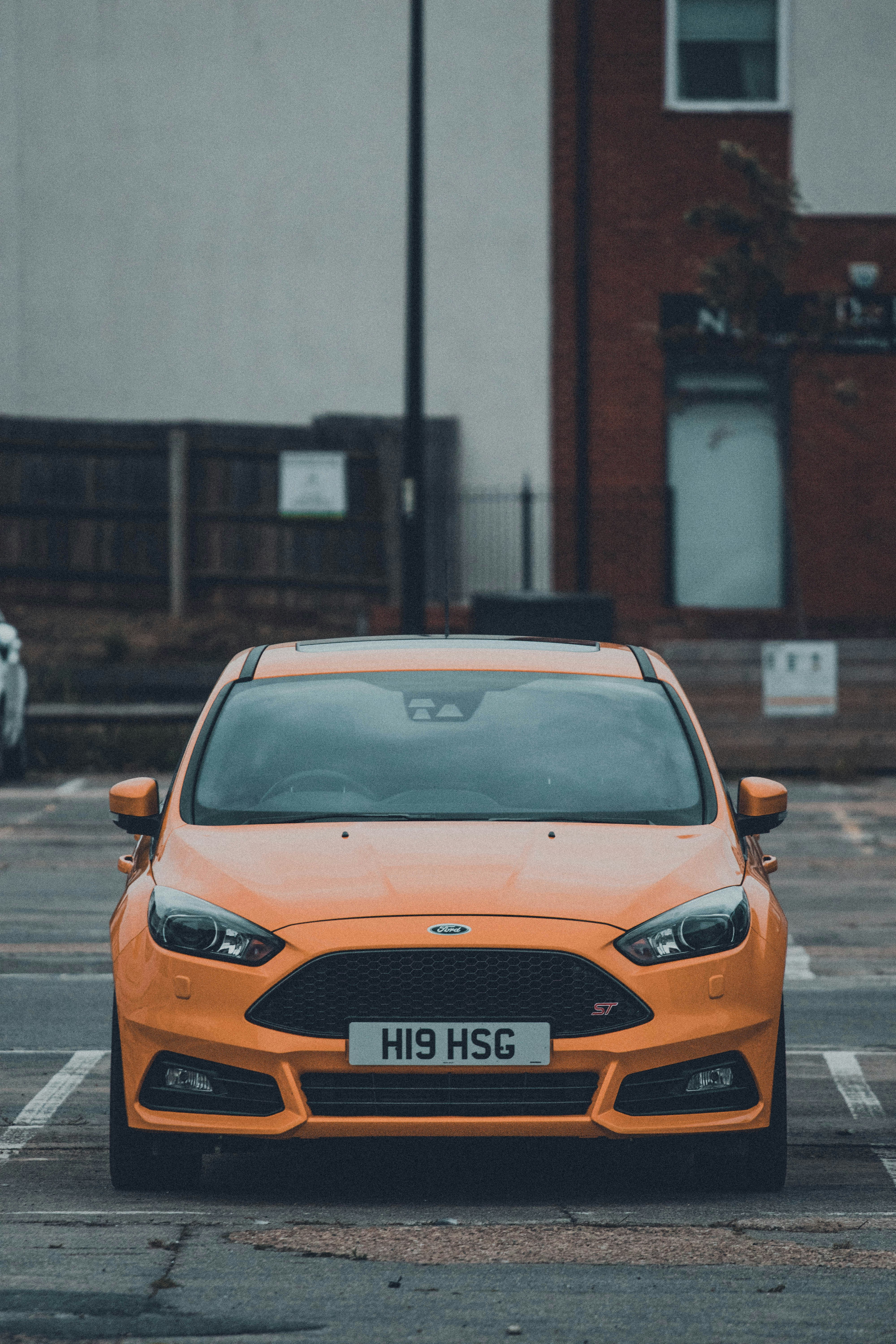 Front-Center Glow: An Orange Ford in a Quiet Urban Parking Lot
