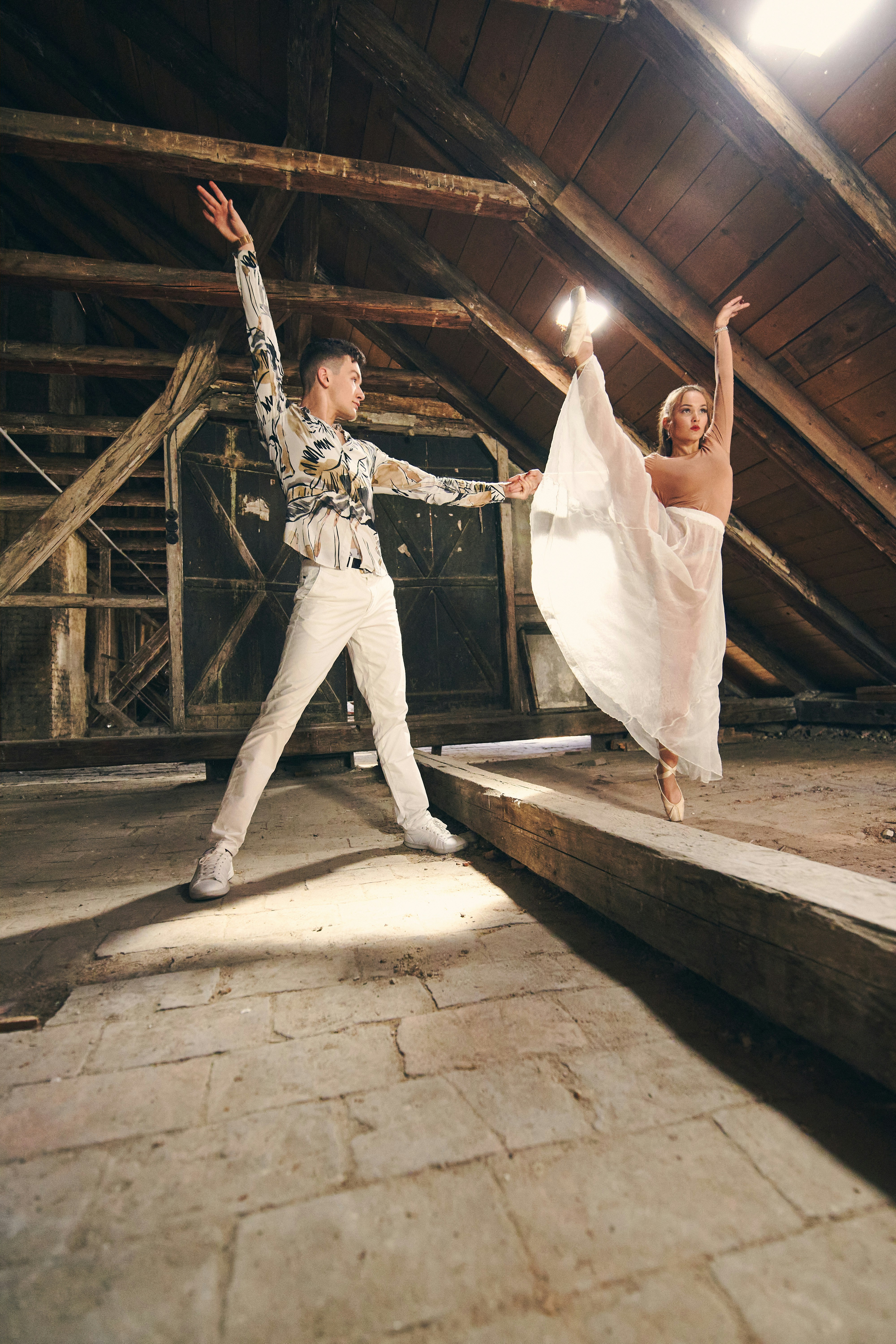 Dance in an Attic: Partners Lean into Light from a Gabled Roof