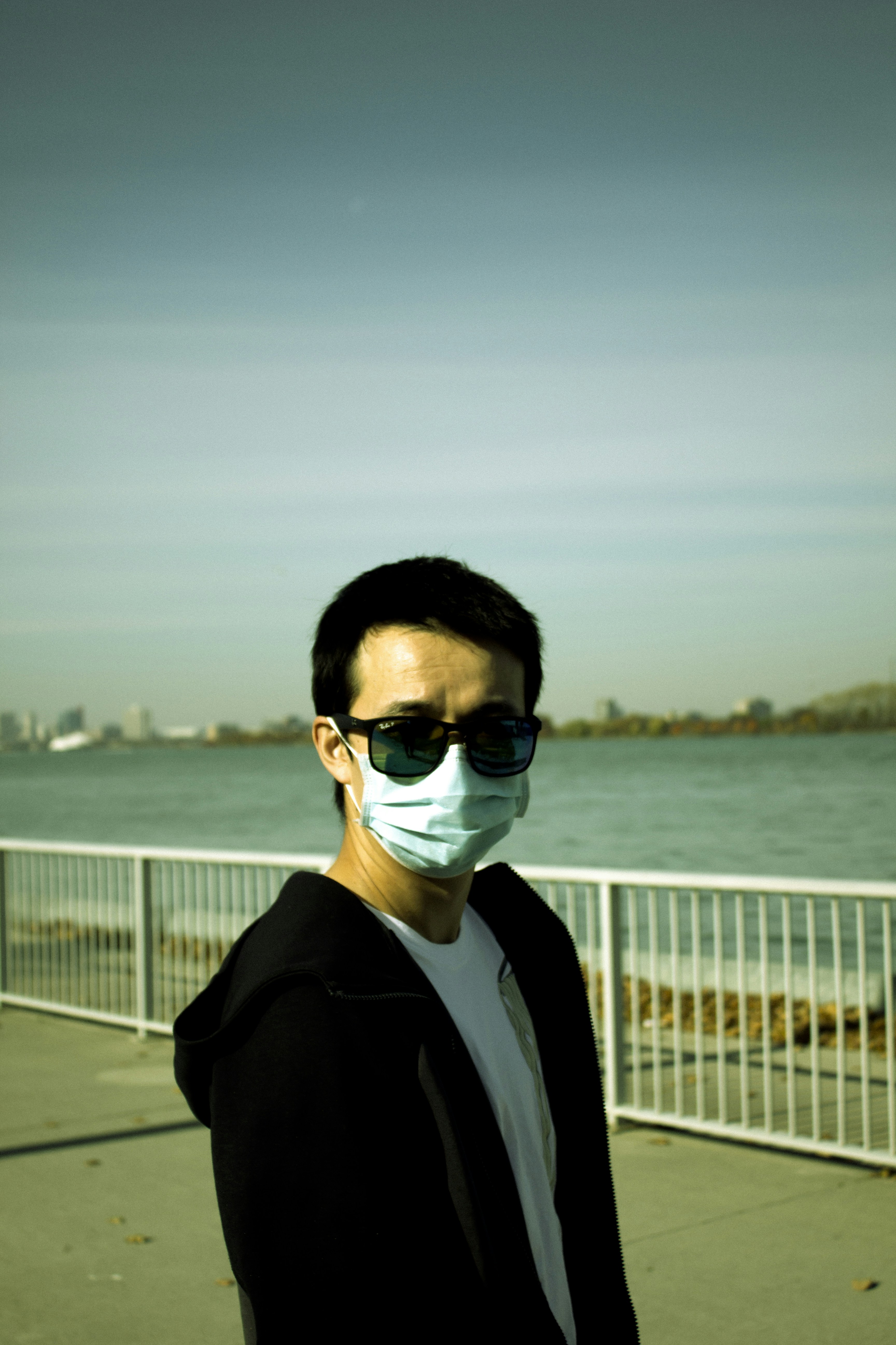man in black suit jacket wearing black sunglasses standing on beach during daytime
