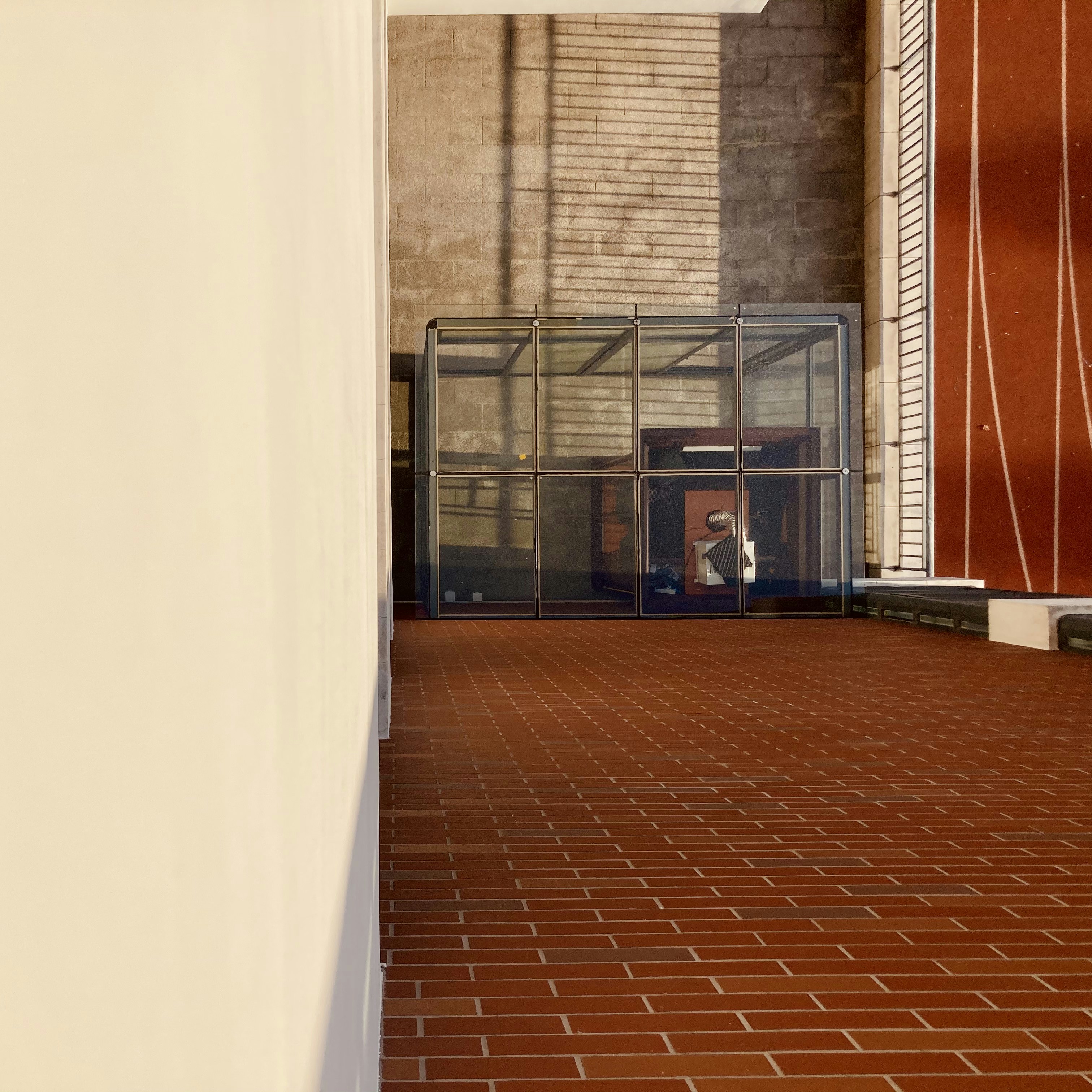 Modern glass enclosure contrasting with textured brick walls, showcasing a blend of architecture and design elements.