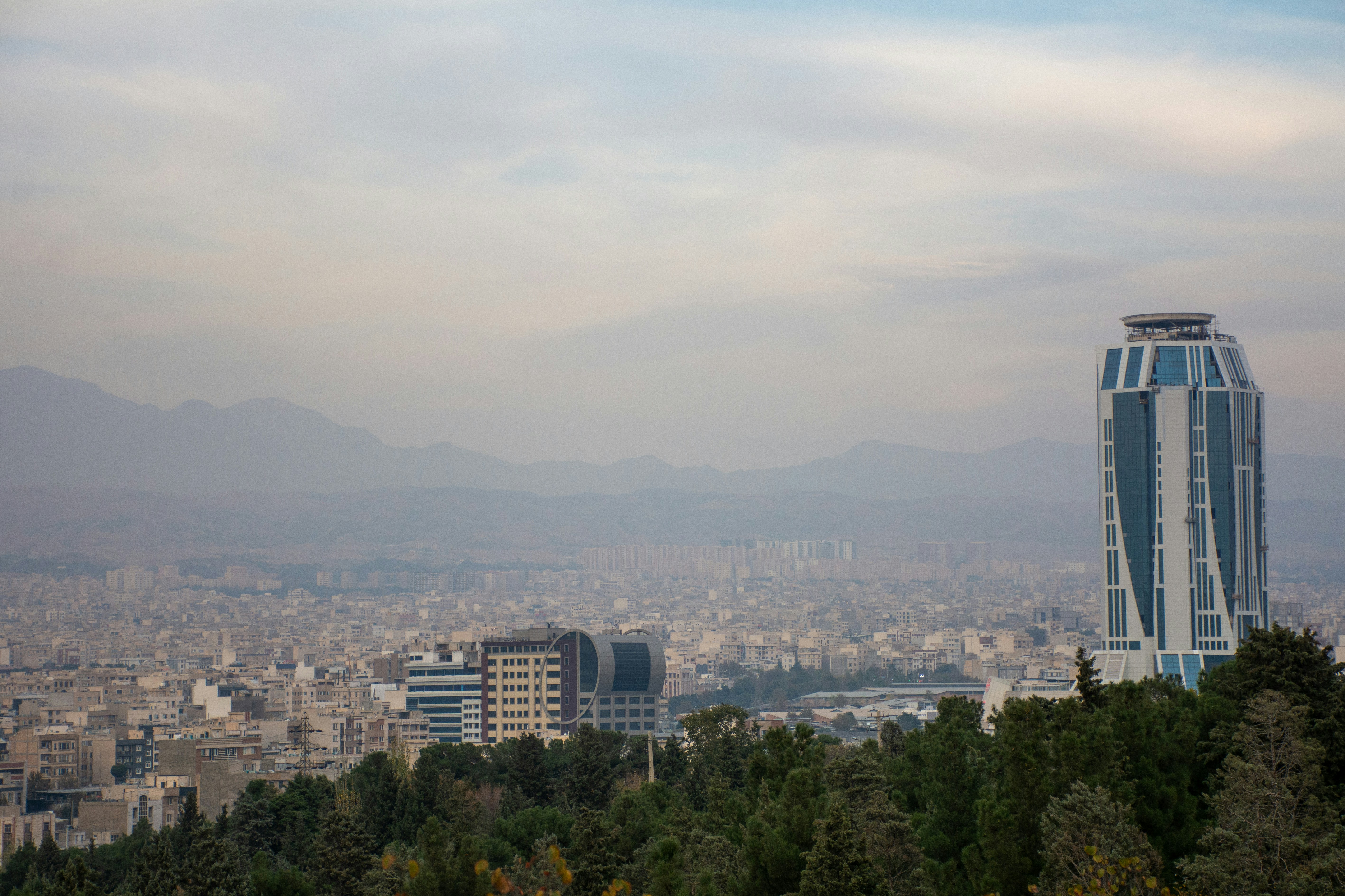 Cityscape featuring modern buildings with a mountainous horizon, showcasing a blend of nature and urban architecture.