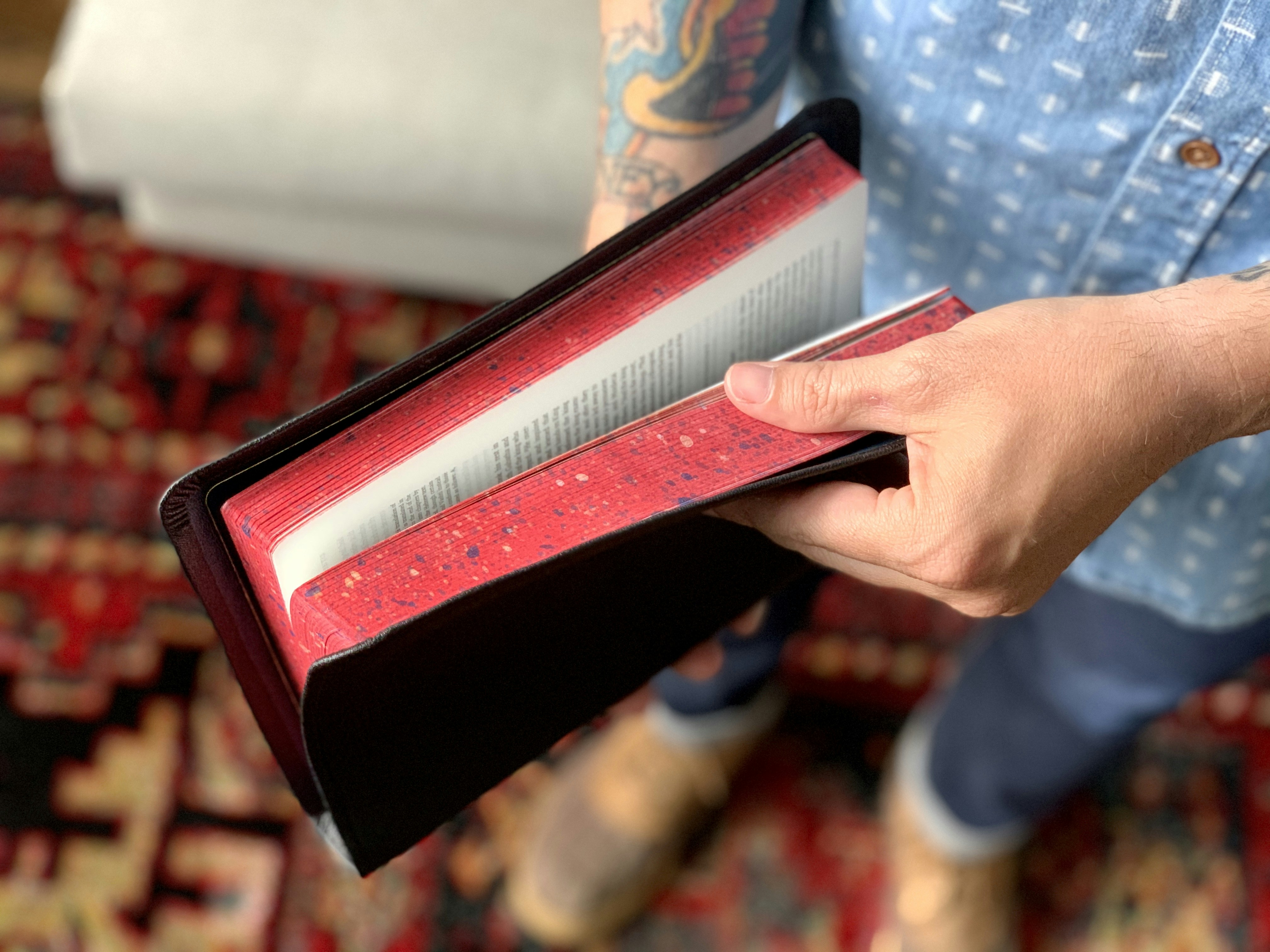 Crimson Journal Clutched by Tattooed Hands on a Patterned Rug