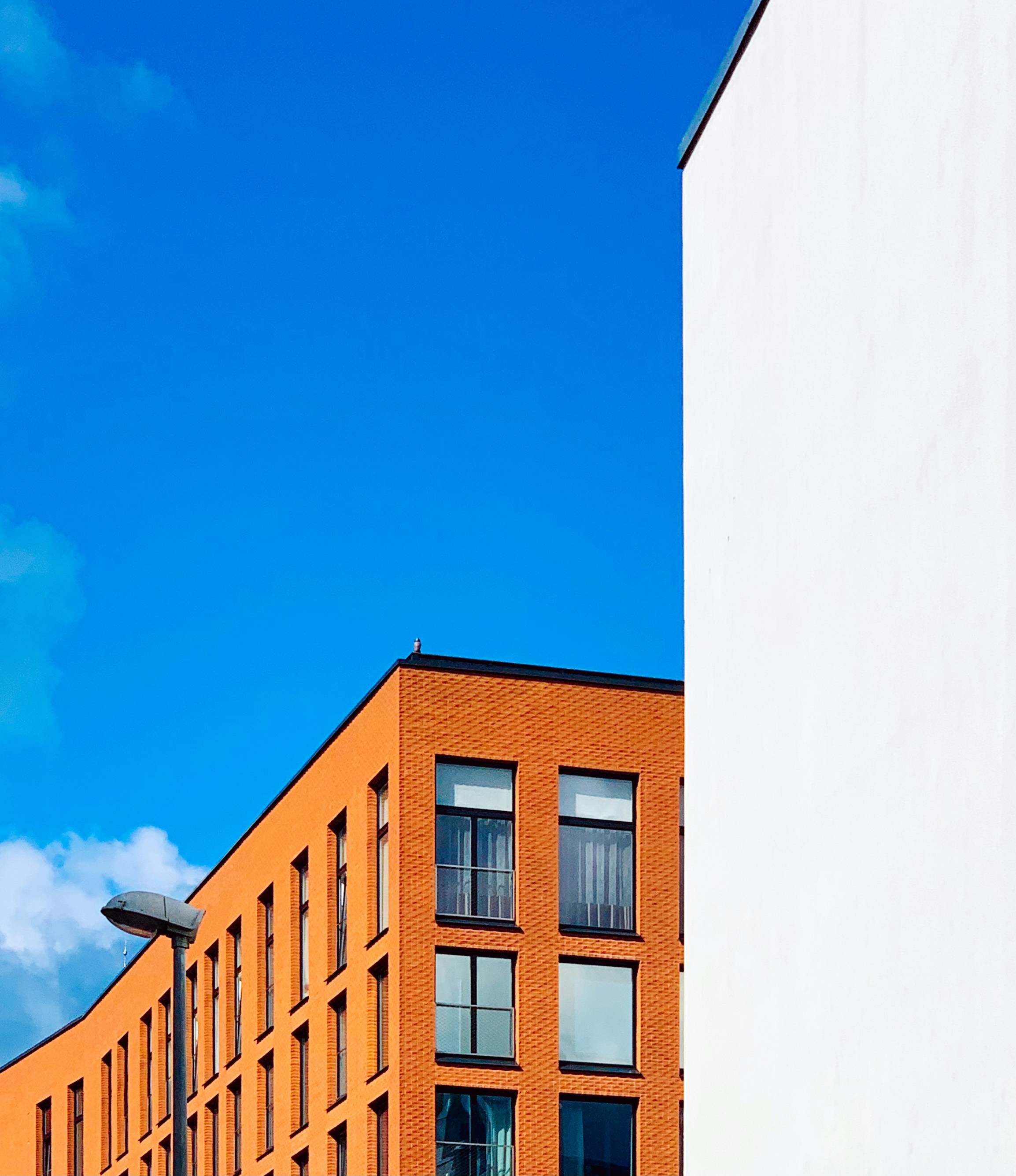 Modern brick building juxtaposed against a bright blue sky, highlighting architectural lines and contrasting colors.