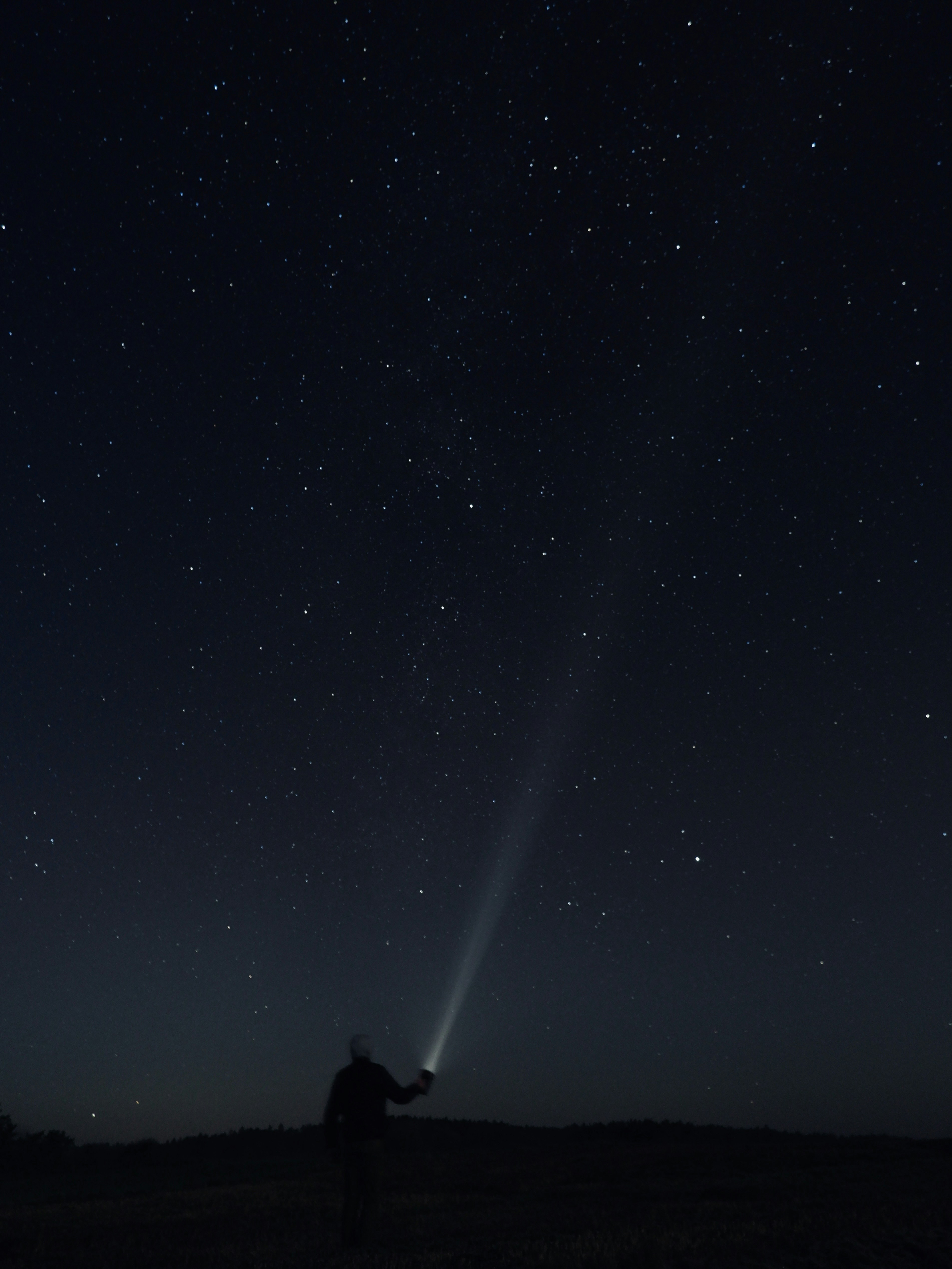 Starfield Beacon: A Lone Silhouette Directs a Narrow Light Across the Night Sky