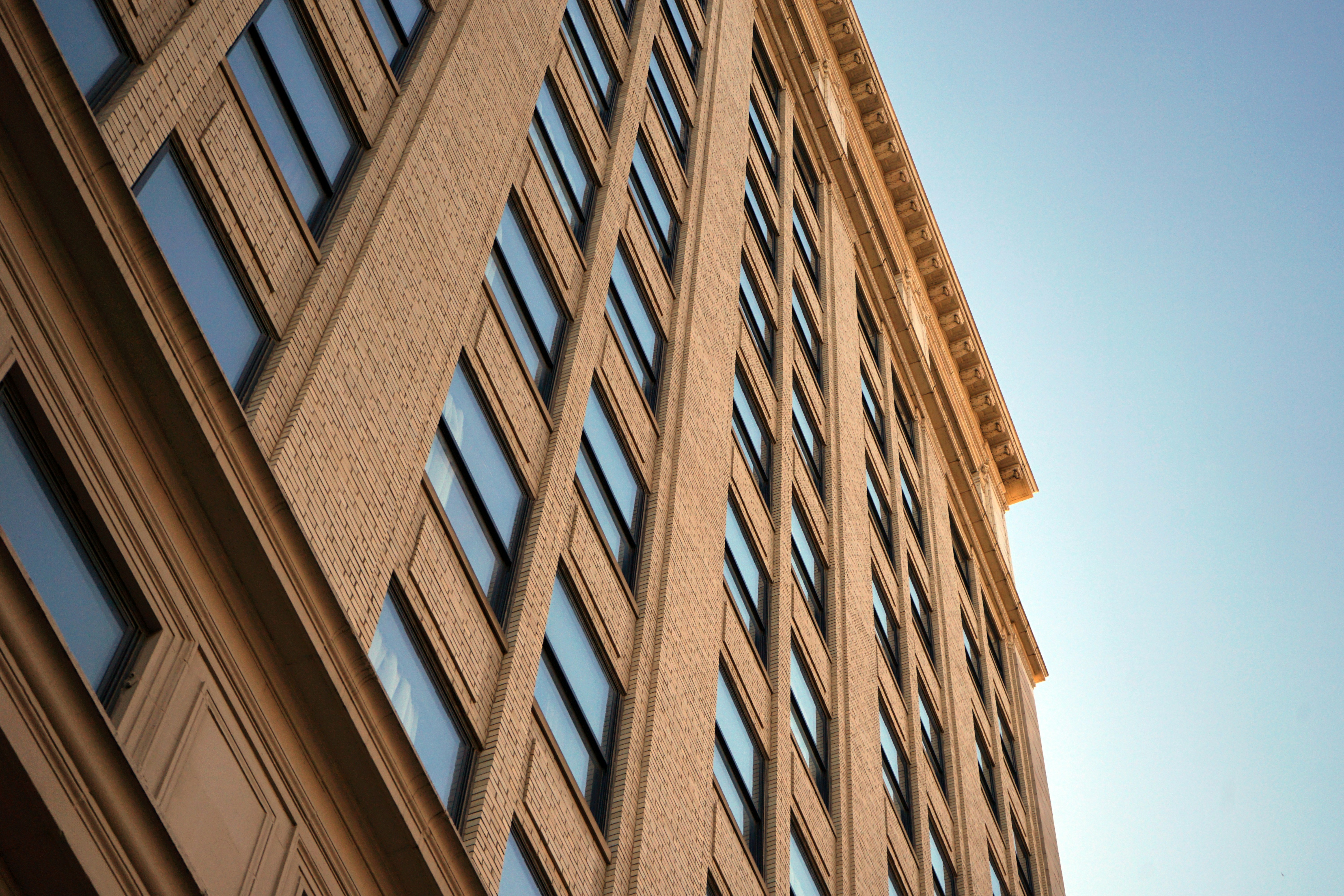 Architectural detail of a historic building captured from a low angle, showcasing its textured brickwork and symmetrical window arrangement.