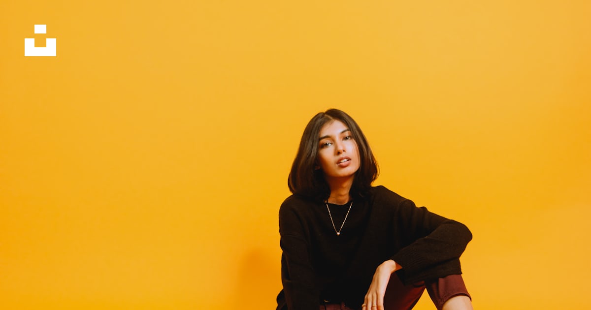 검은 긴 소매 셔츠와 검은 바지를 입은 여자가 노란 바닥에 앉아 있다 사진 Unsplash의 무료 스타일 이미지