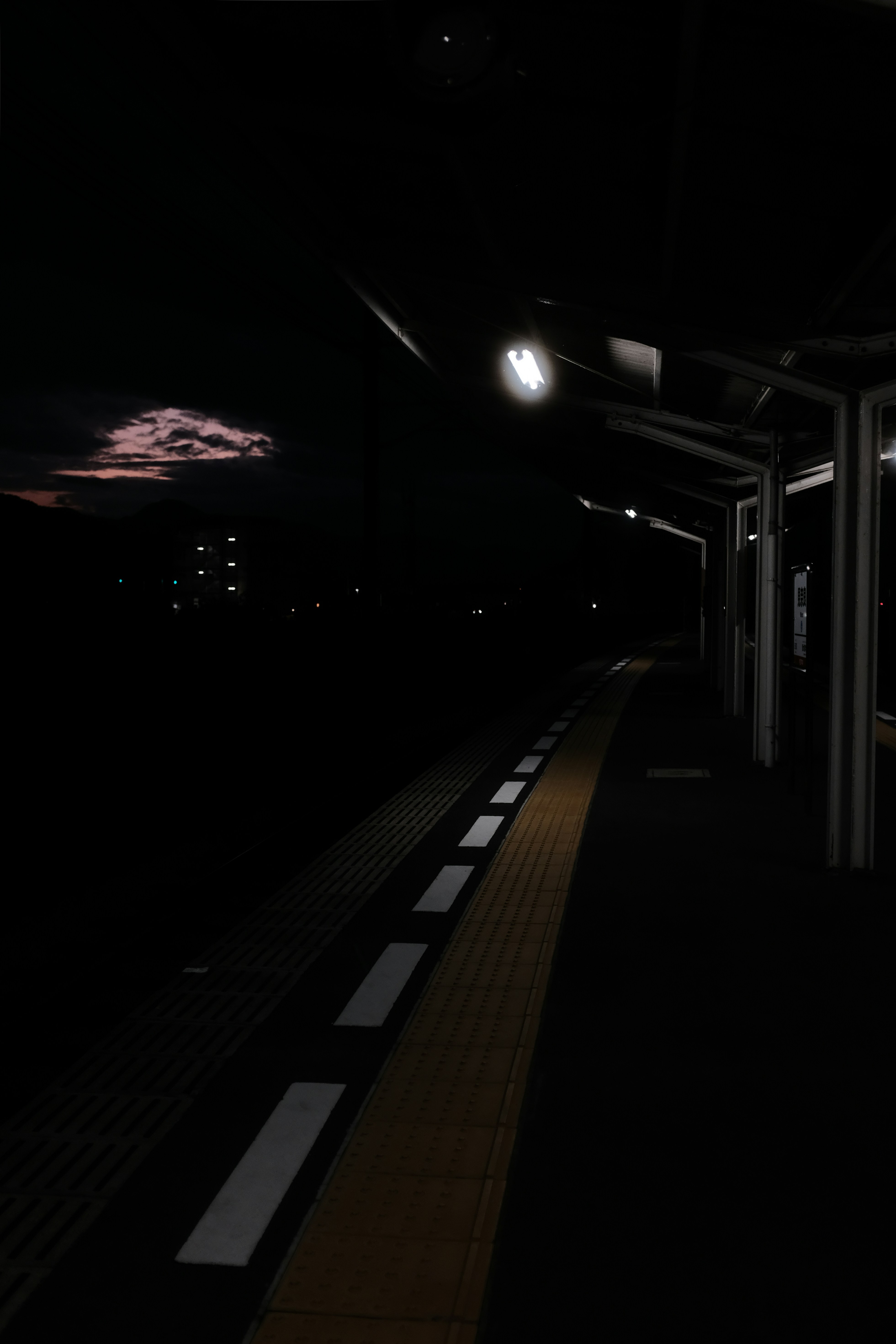 Single Overhead Light Casts Quiet Drama Across a Night Platform