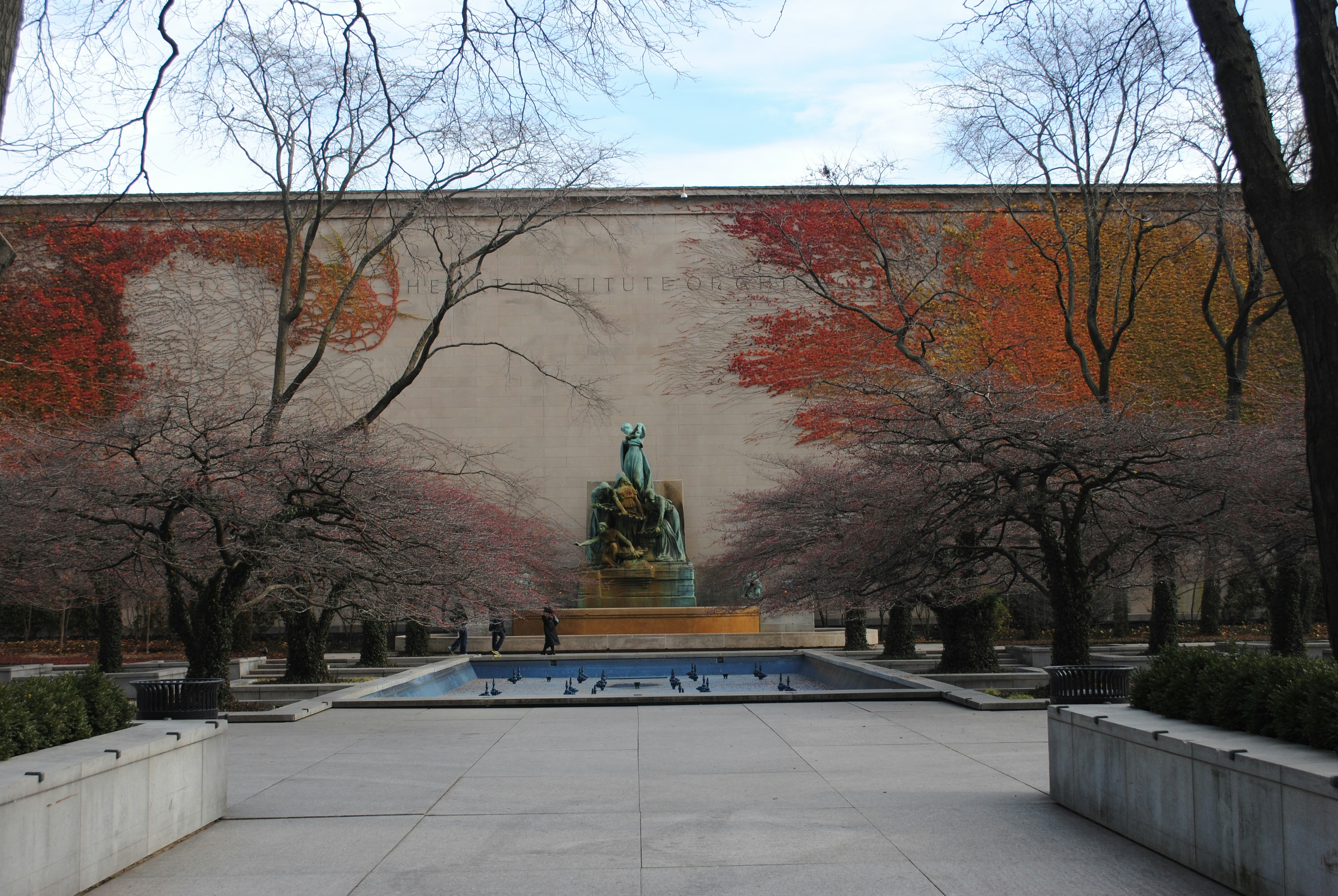 Bronze Sentinel Framed by Autumn's Red and Gold Corridor