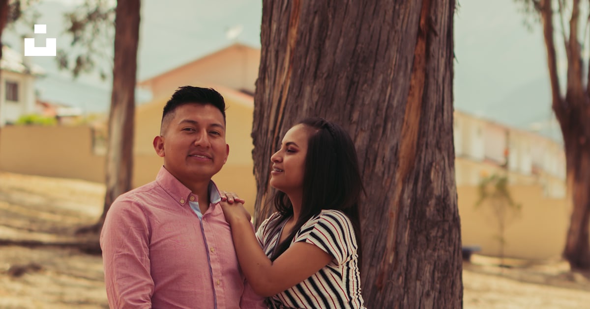 Man In Pink Dress Shirt And Black Pants Standing Beside Woman In Black